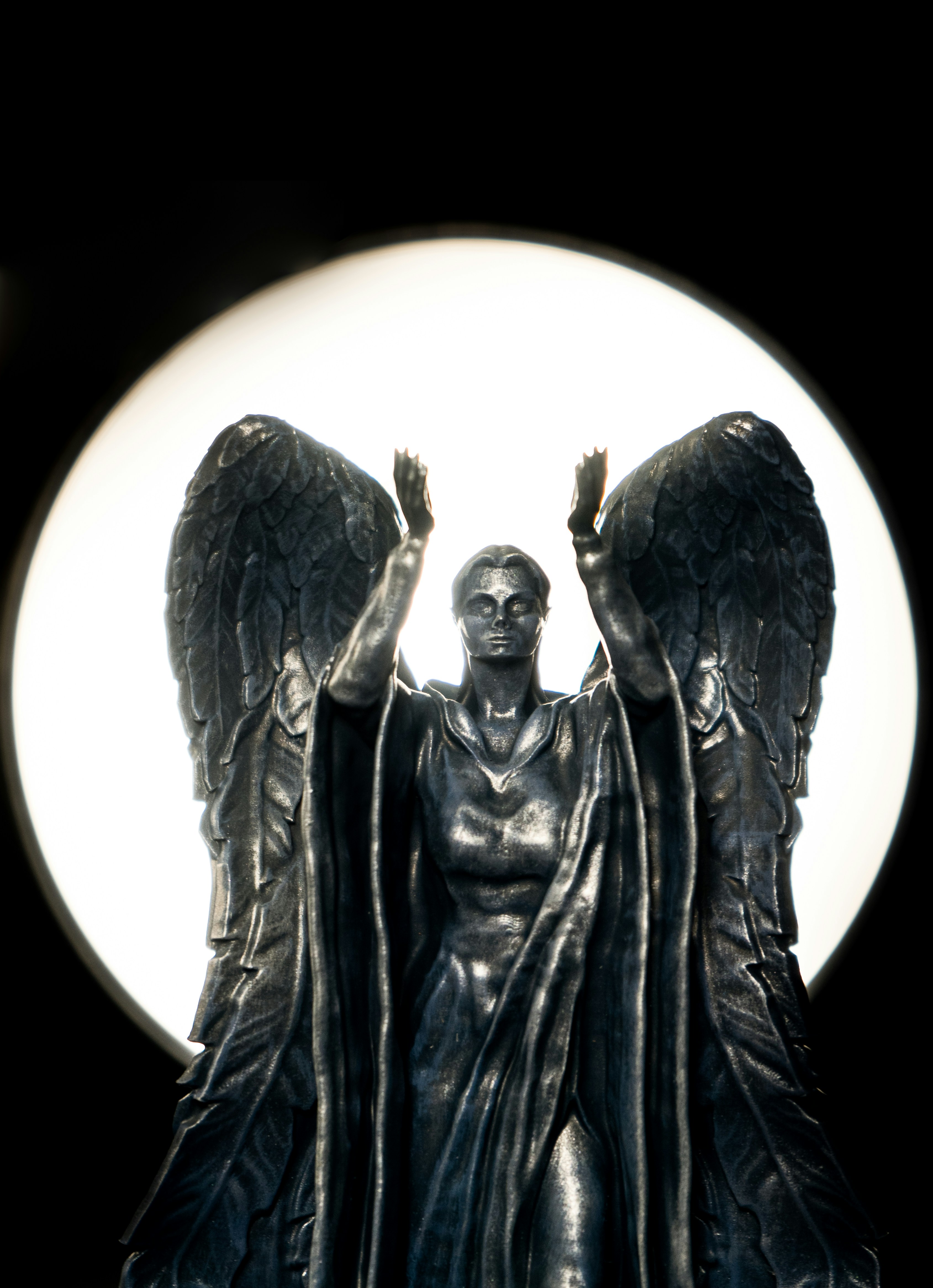 A statue of an angel holding two hands in front of a full moon photo ...