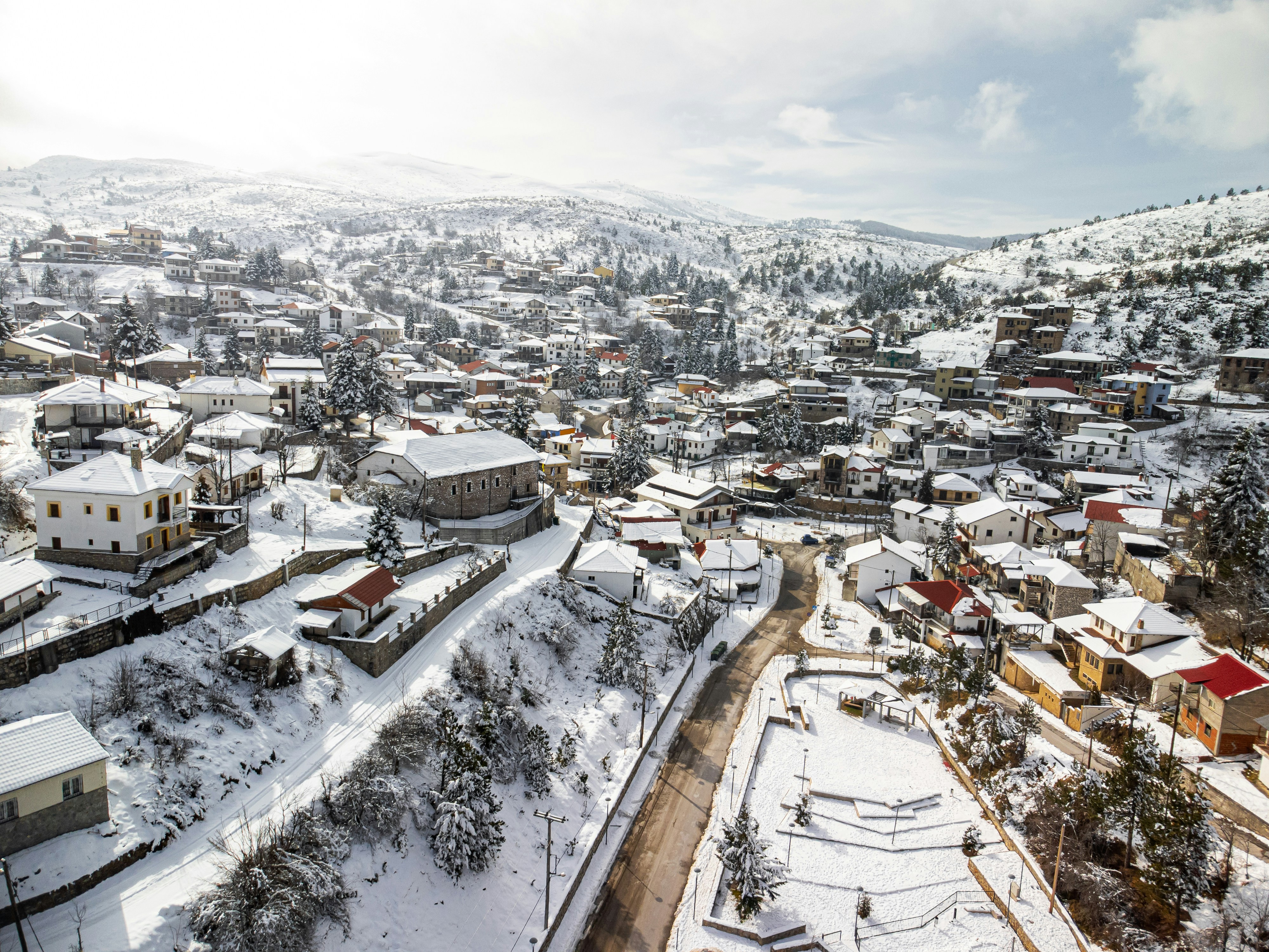 A snow covered town surrounded by mountains and trees photo – Free ...