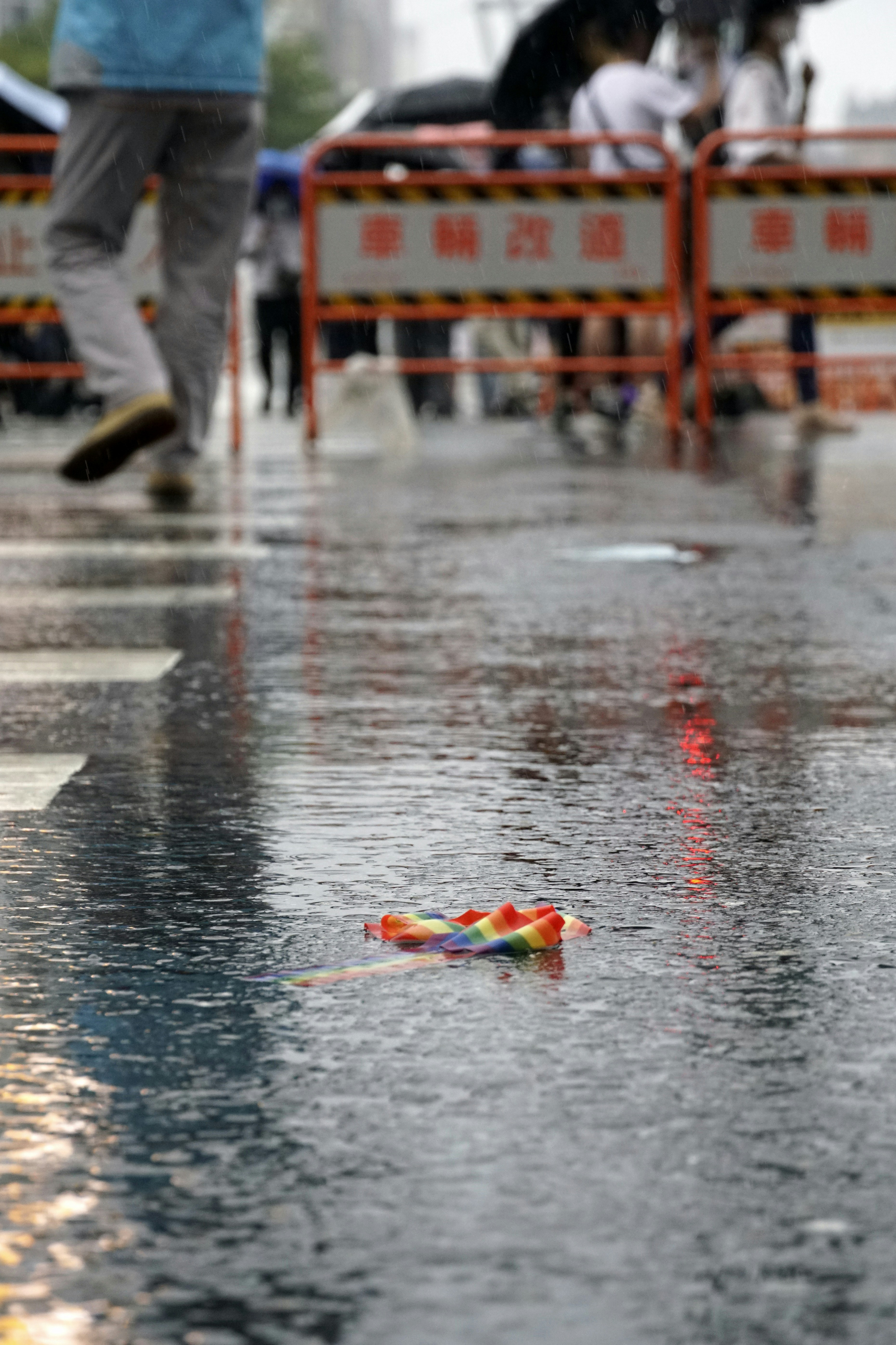 Rainbow Ribbon on a Rain-Washed Street Between Barricades
