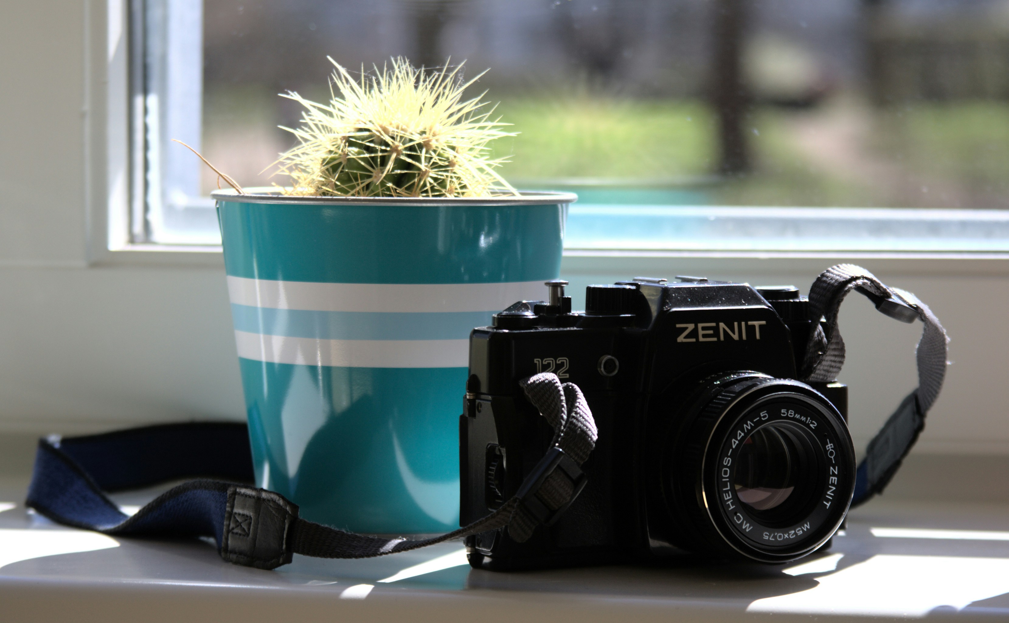 Sunlit Windowsill: Teal Planter and a Vintage Zenit Camera at Rest