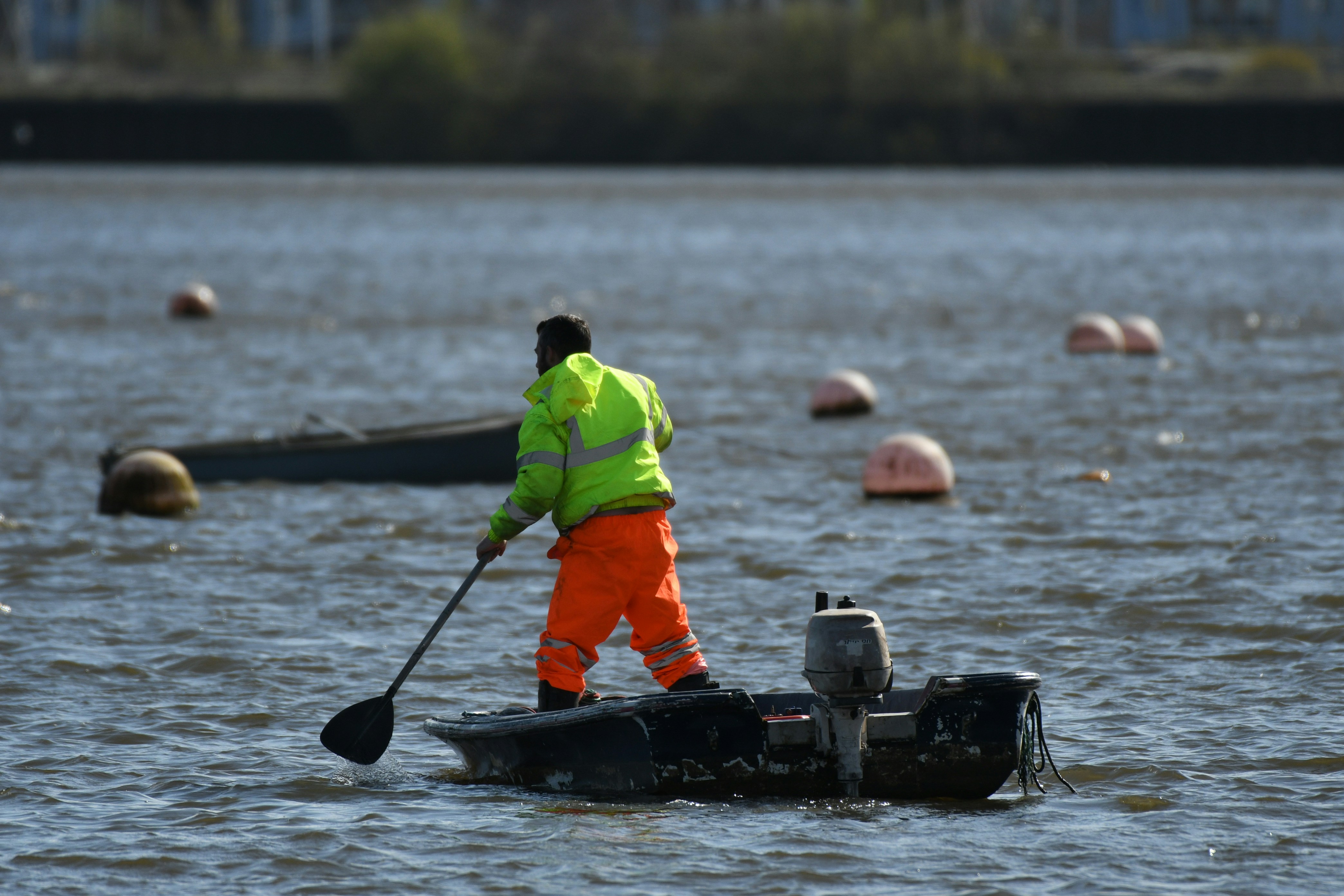 Neon-Clad Operator Steering a Compact Workboat Through Buoys