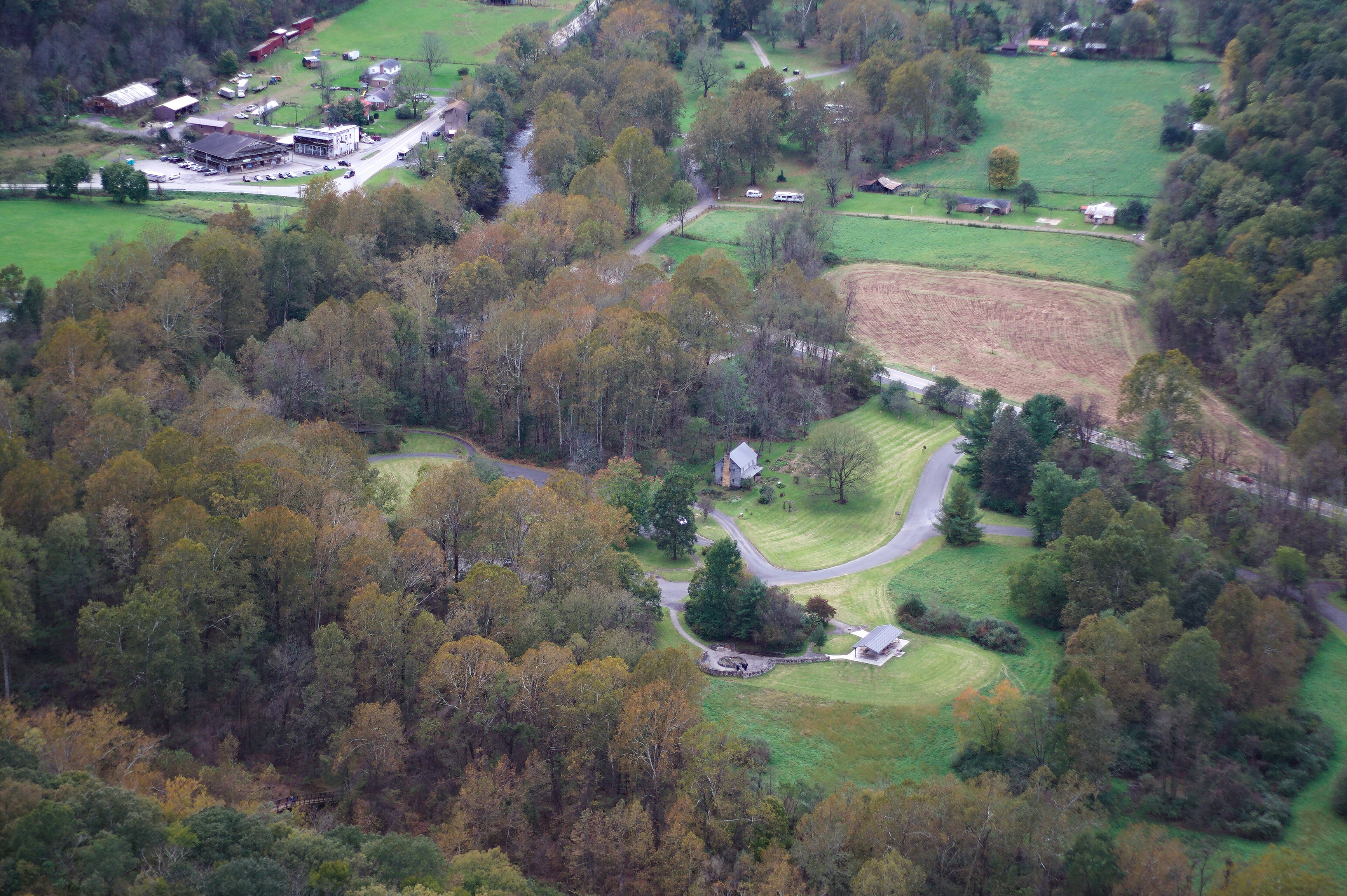 Aerial view of a rural landscape with winding roads and patchy autumn foliage.