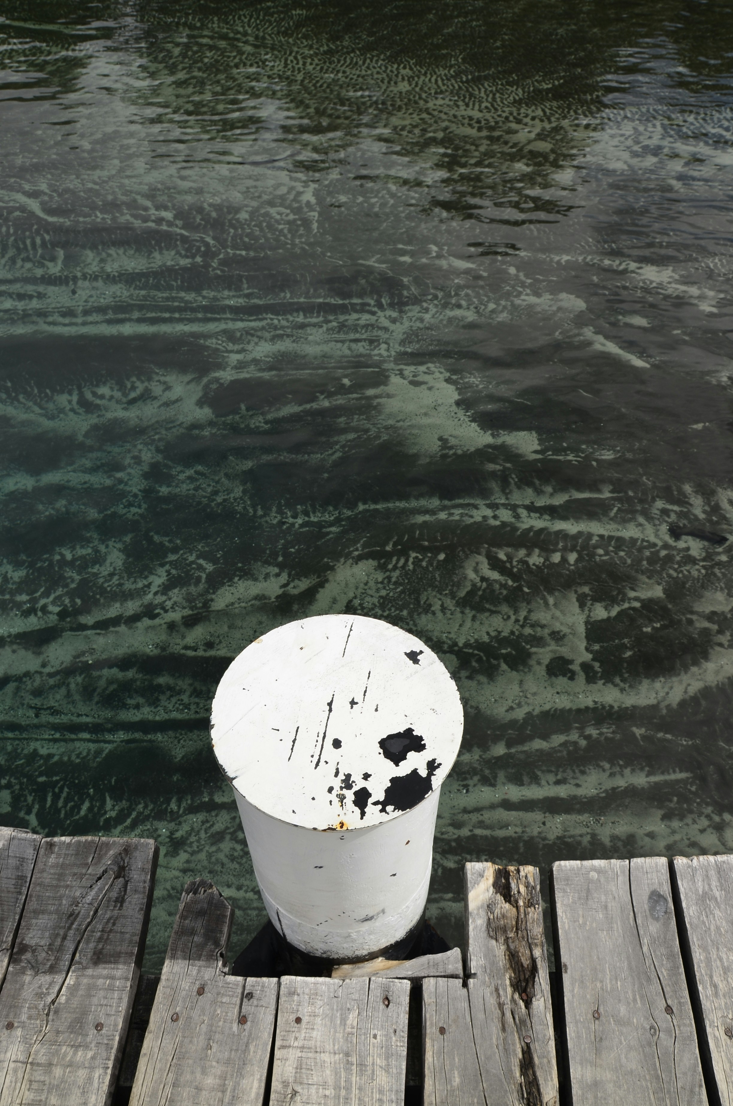 Weathered Sentinel at the Dock: White Bollard Above Quiet Turquoise Water