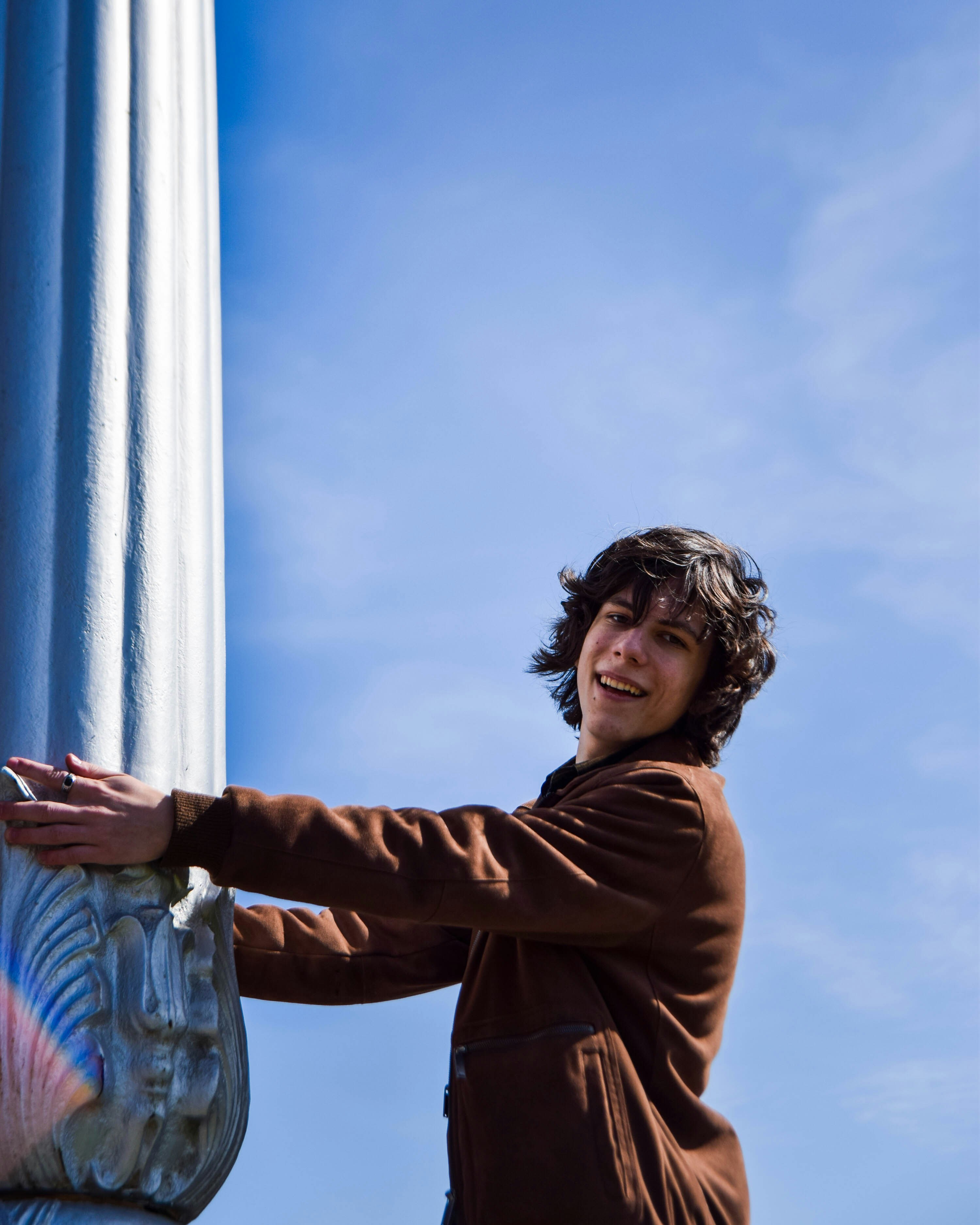A man leaning against a pole with a blue sky in the background photo ...