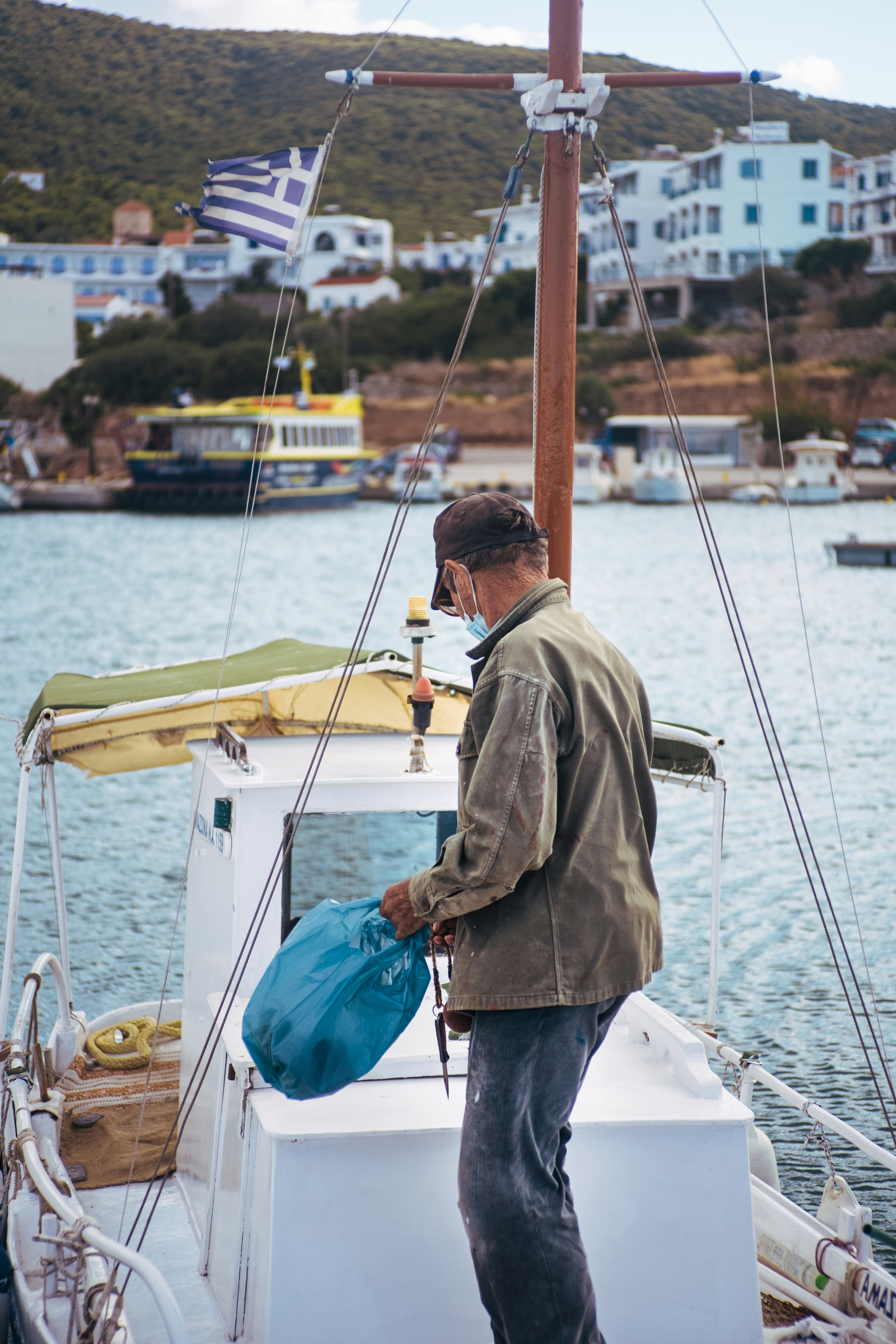 Blue Bag, Quiet Duty: A Sailor with a Mask on a Sunlit Dock