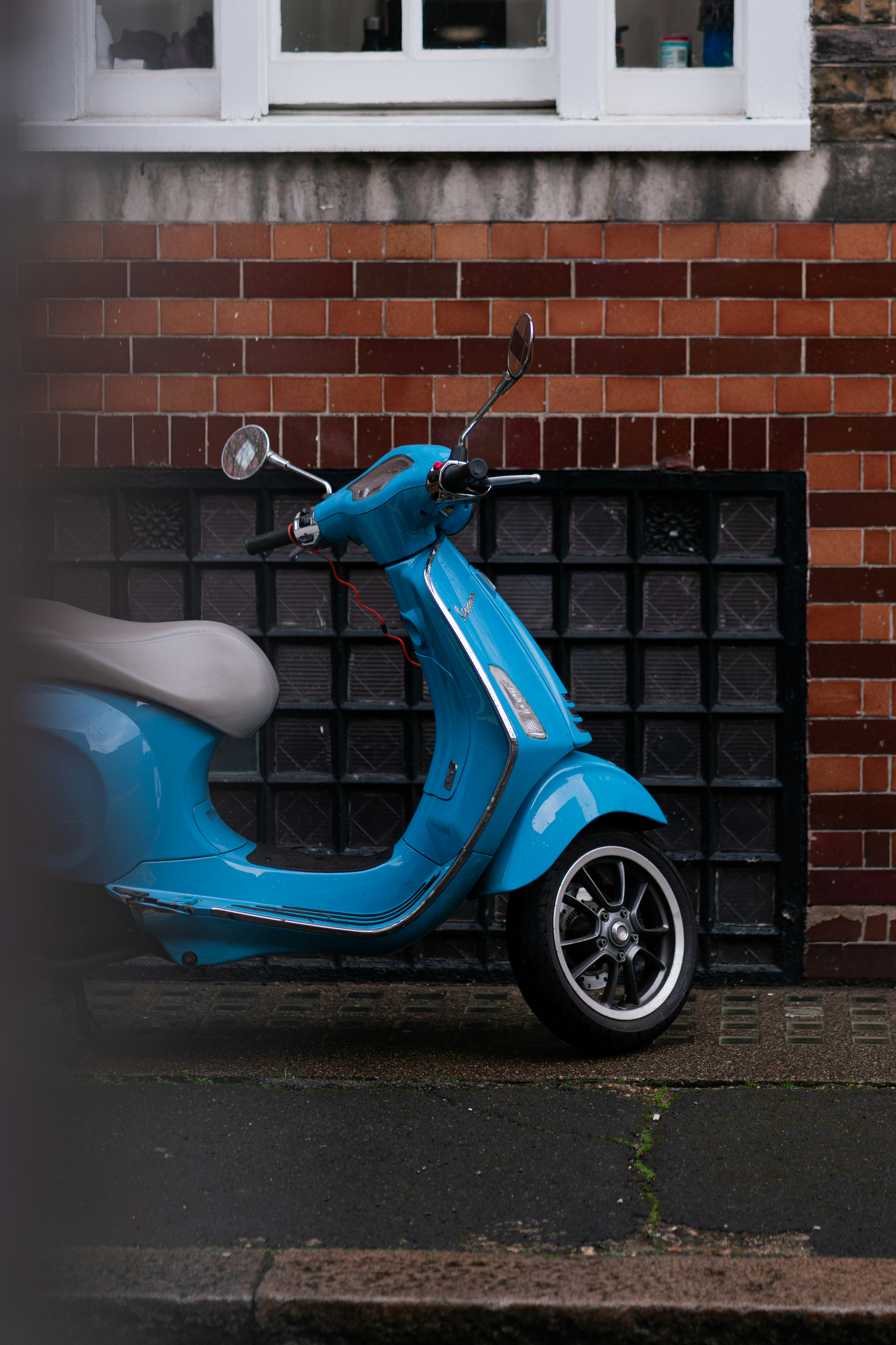 a blue scooter parked in front of a brick building
