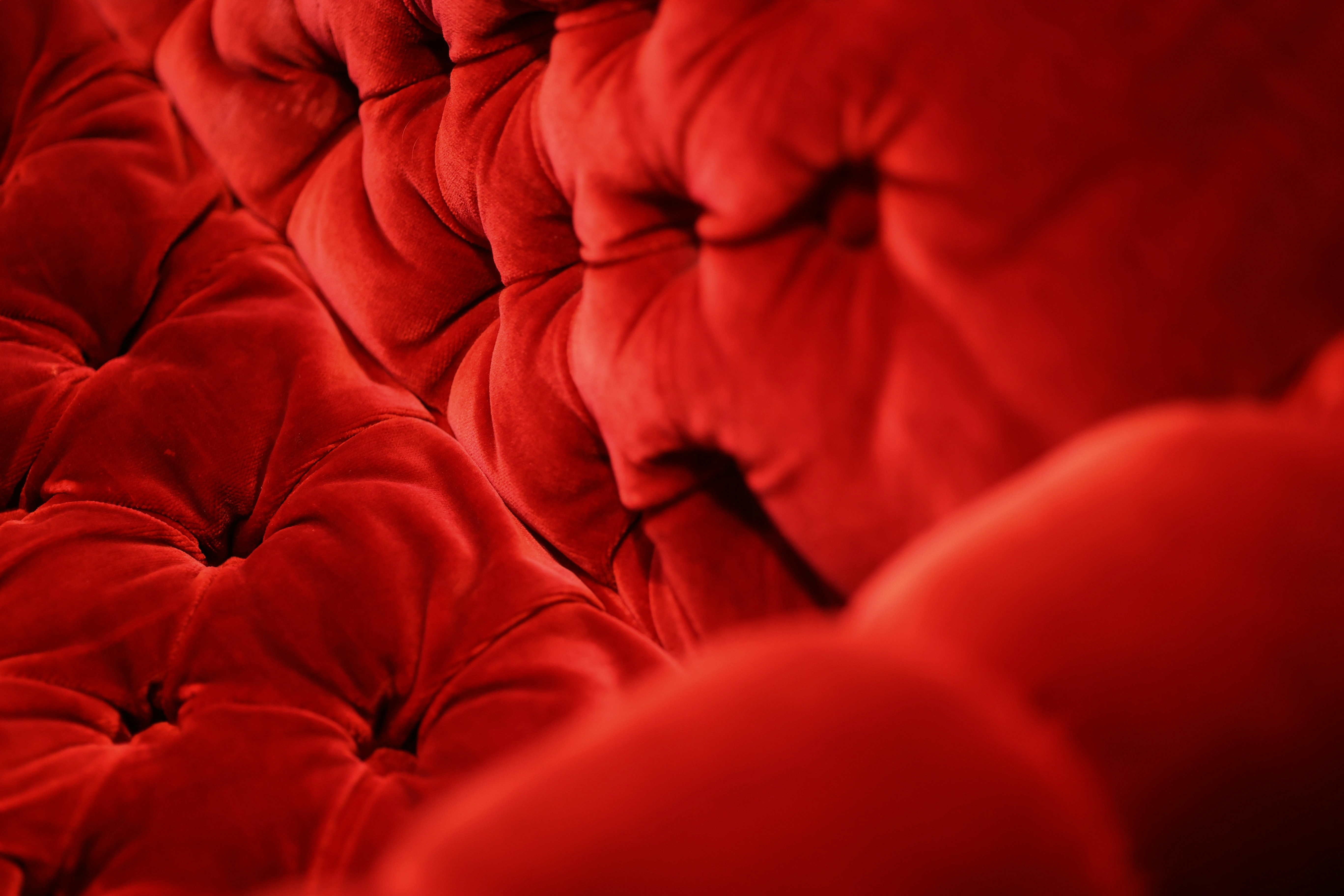 Close-up of a red tufted fabric with intricate folds and shadows.