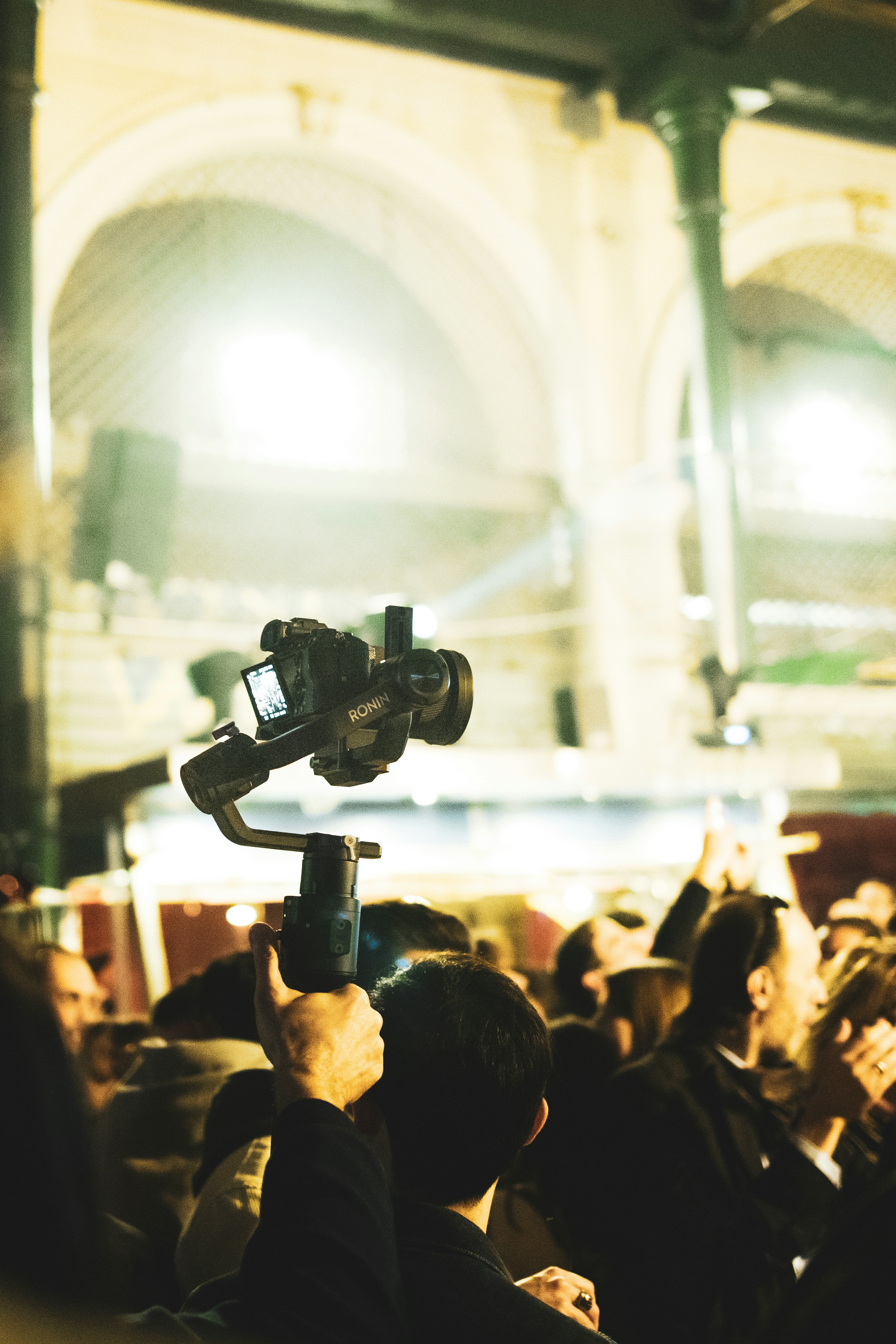 Gimbal in the Crowd: Handheld Rig Steadying Night in a Marble-arched Hall