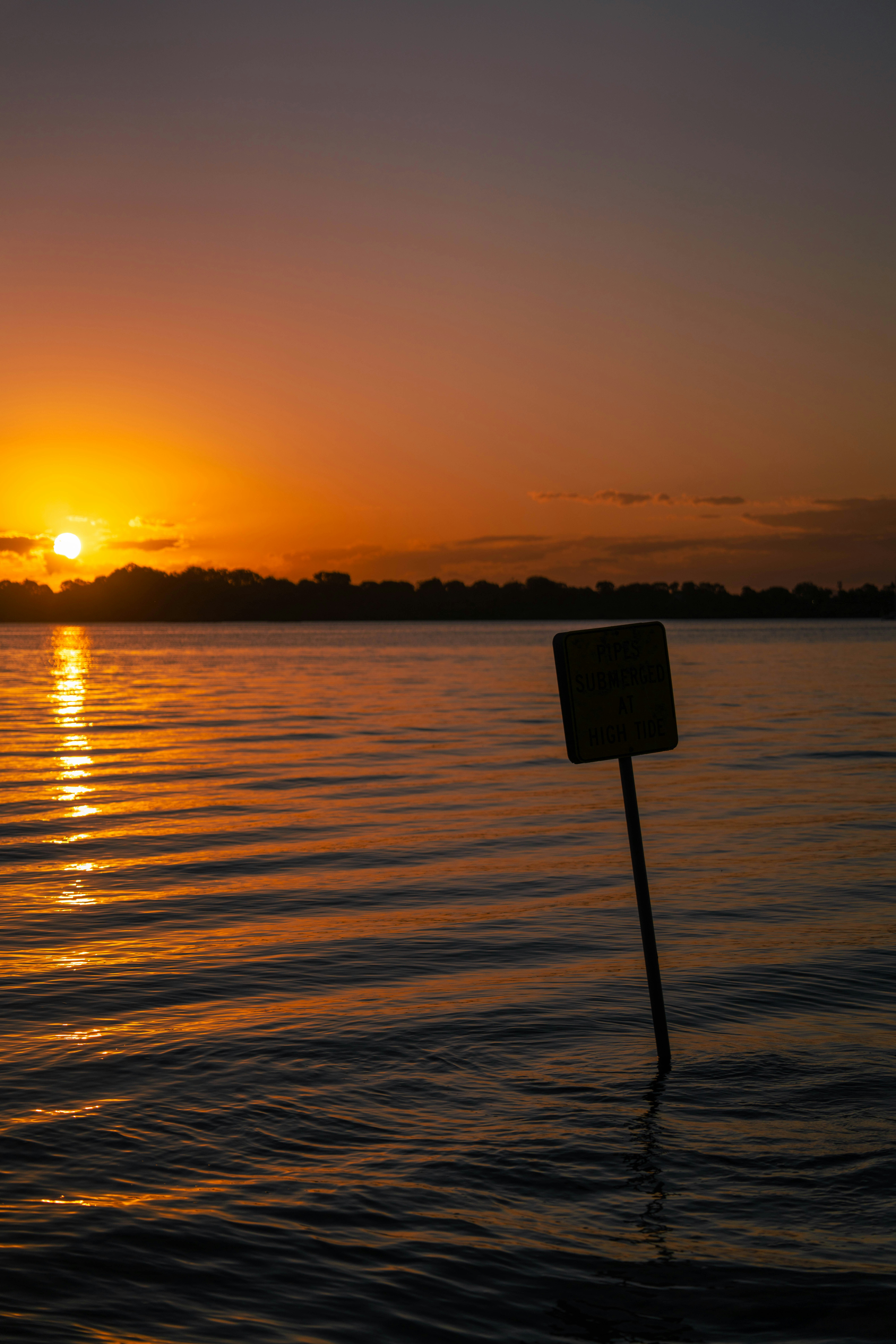 Tilted Signpost in a Golden Sunset over Quiet Waters