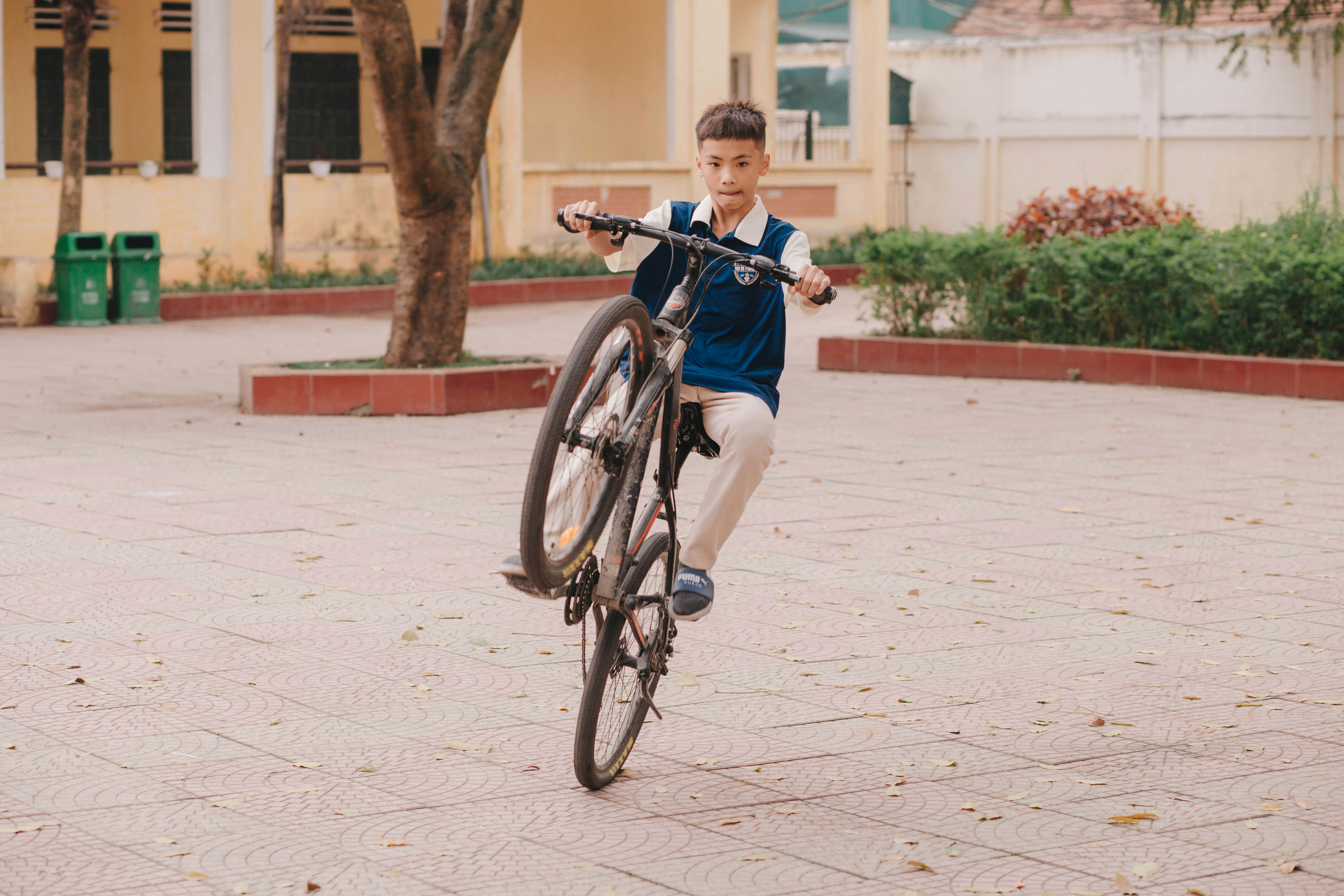 A young boy is riding a bicycle in a courtyard photo – Free Boy Image ...