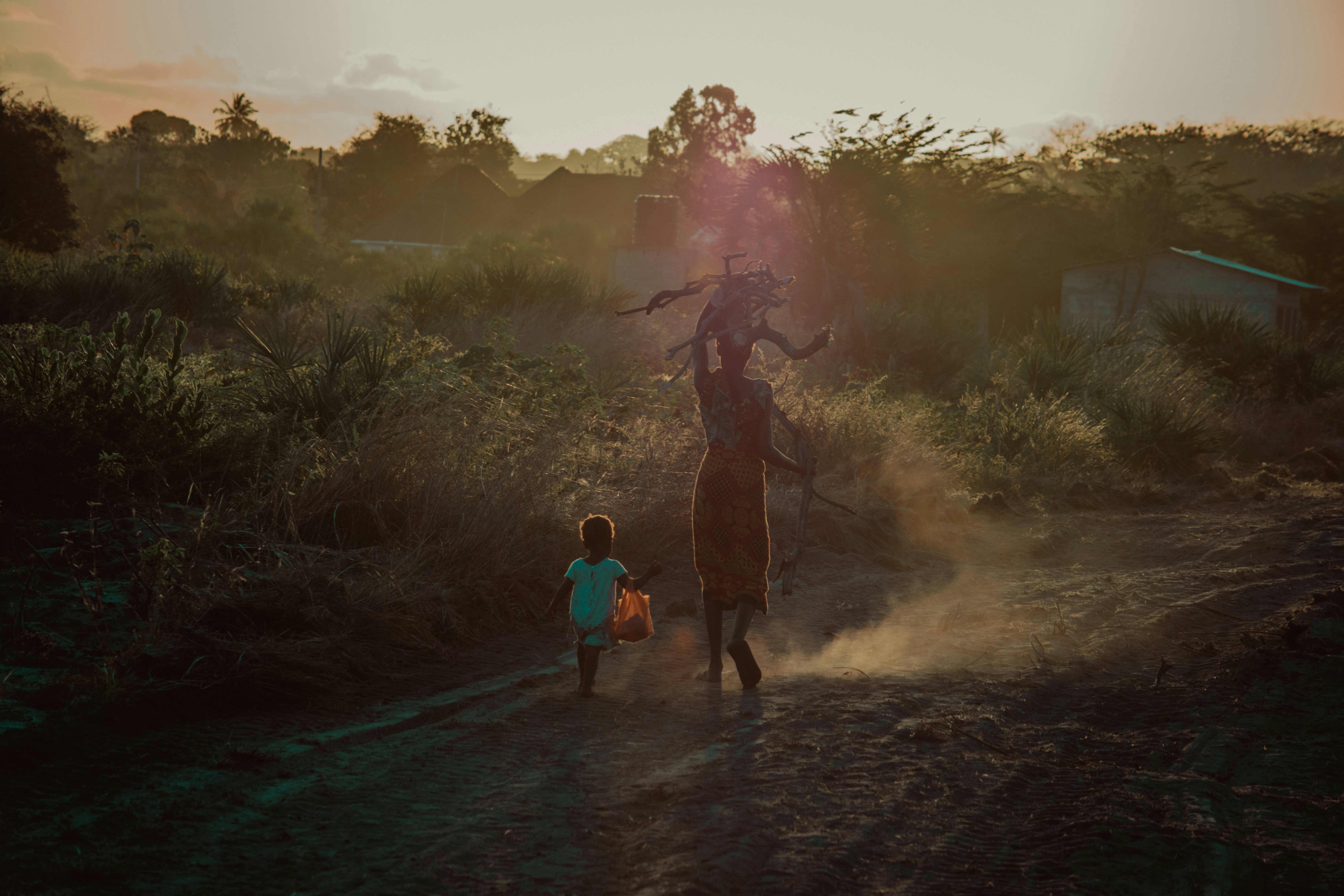 Dusk Silhouette: A Mother and Child on a Dusty Village Path