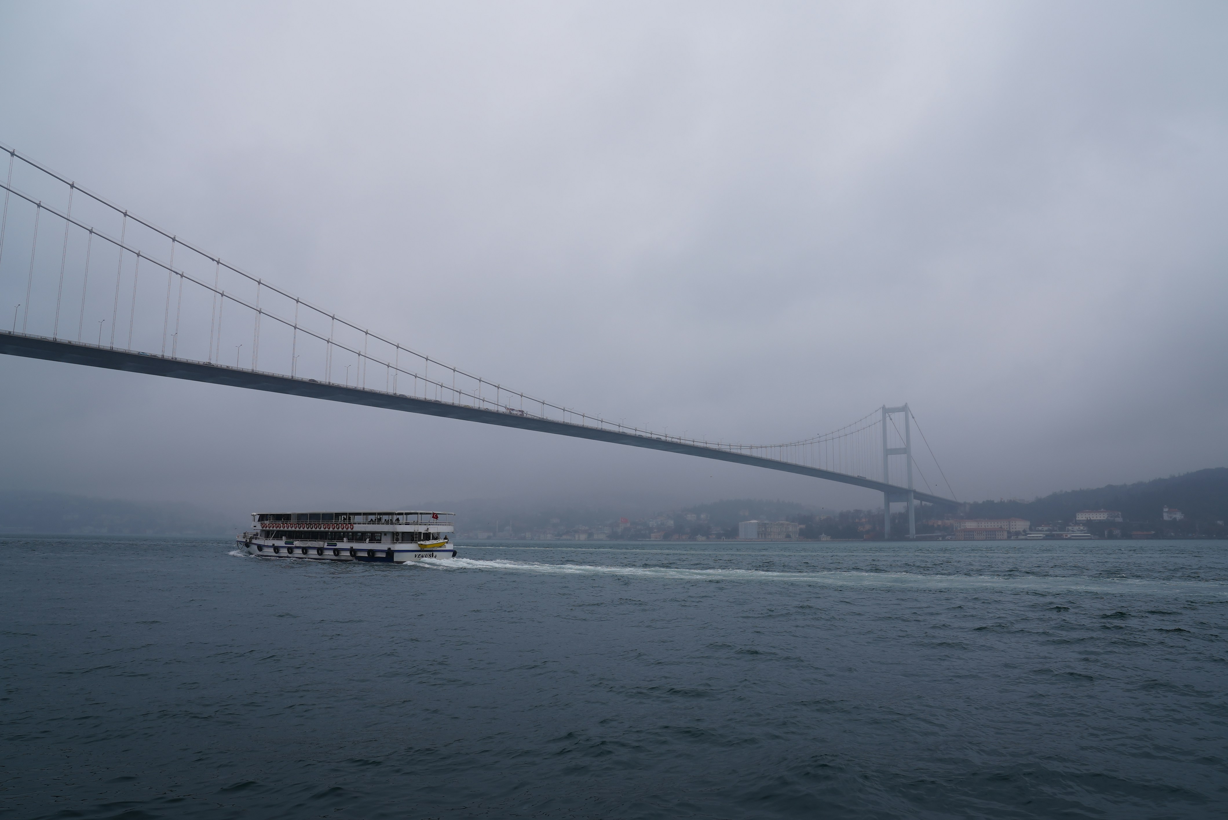 A boat traveling under a bridge on a cloudy day photo – Free Boat Image ...