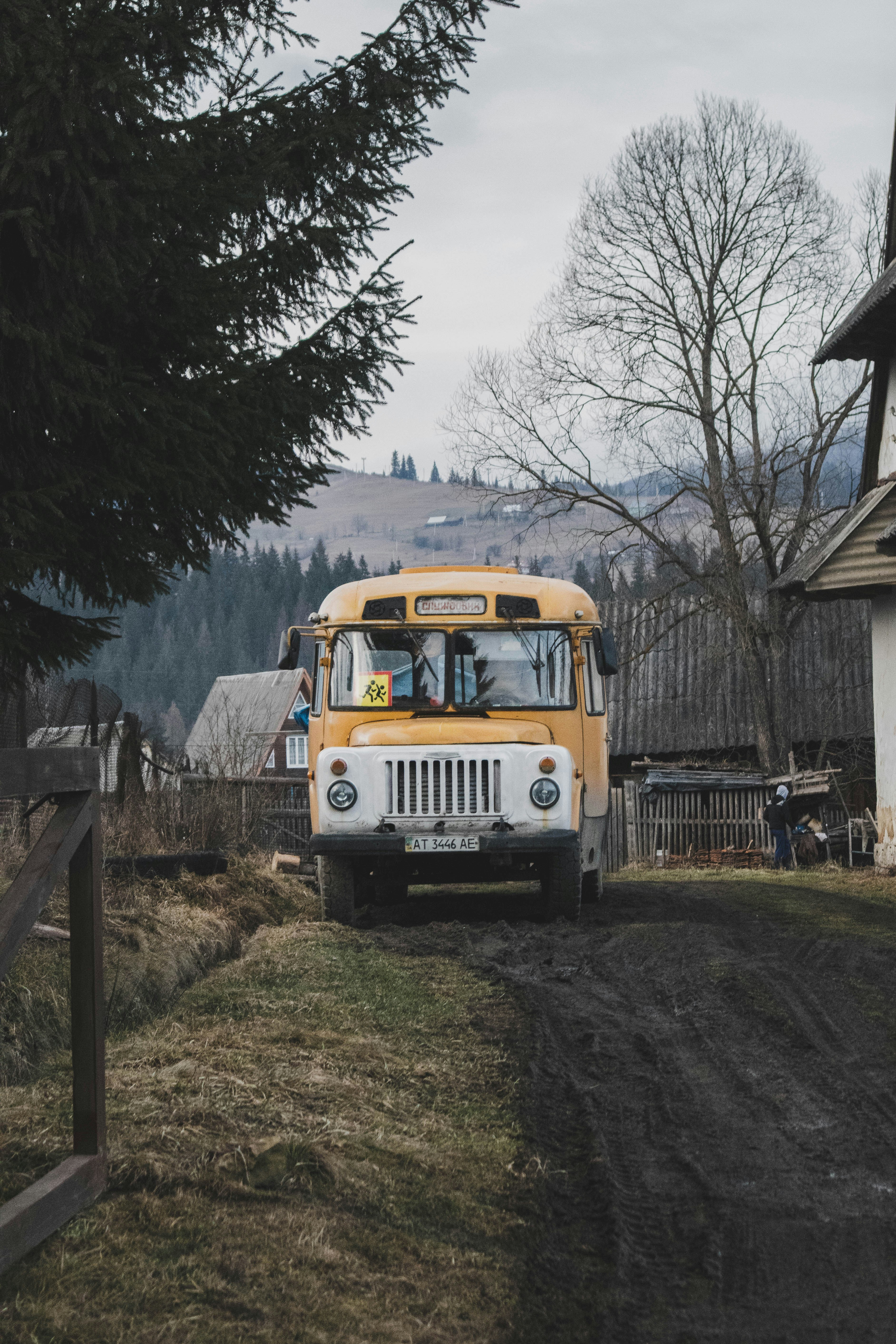 Old yellow bus anchors a muddy rural lane beneath bare trees