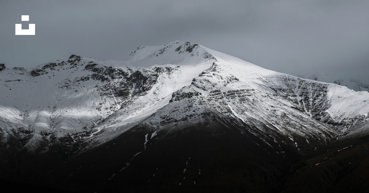 Une Montagne Couverte De Neige Sous Un Ciel Nuageux Photo Photo