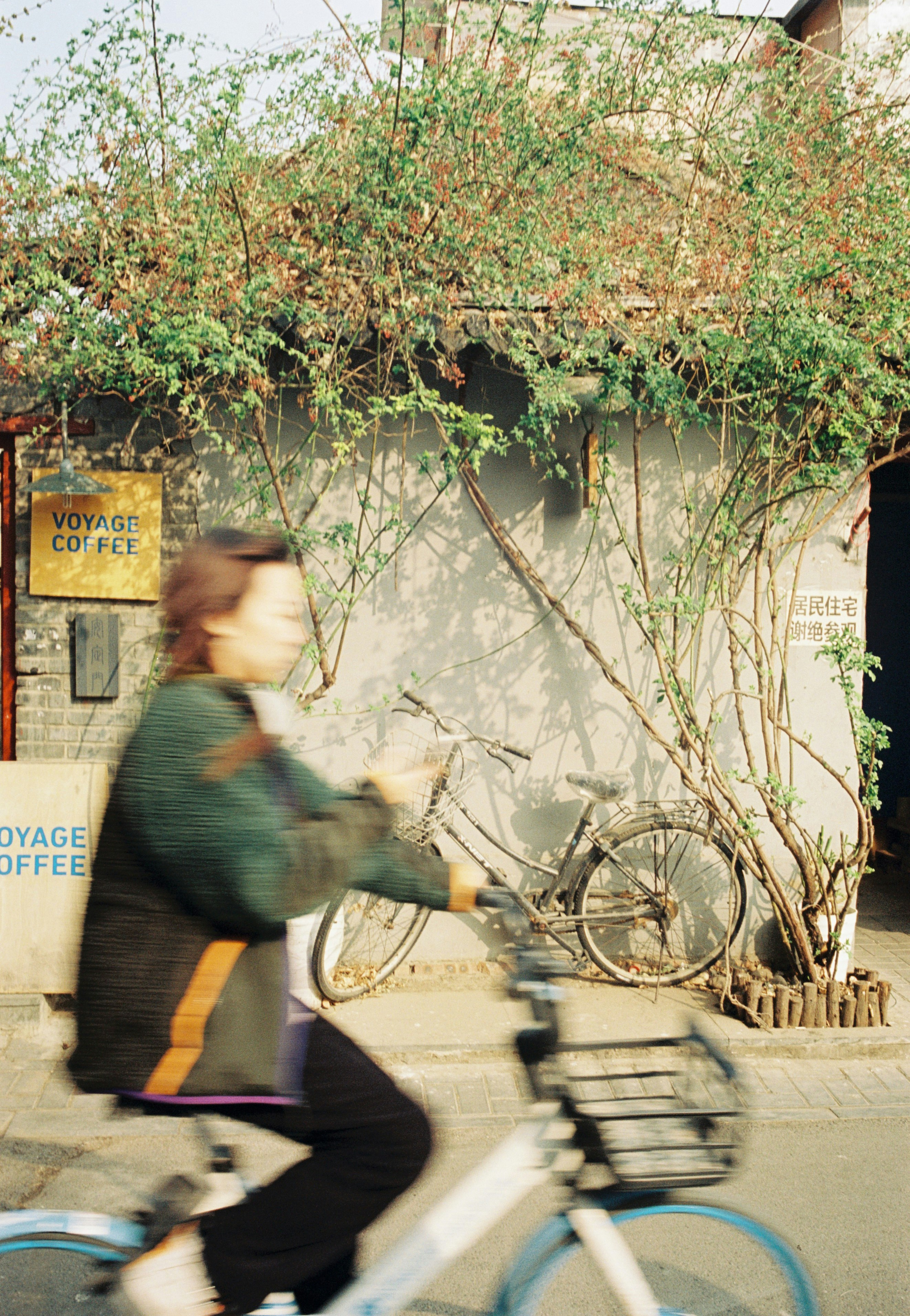 Pedestrian in motion past a sunlit cafe wall