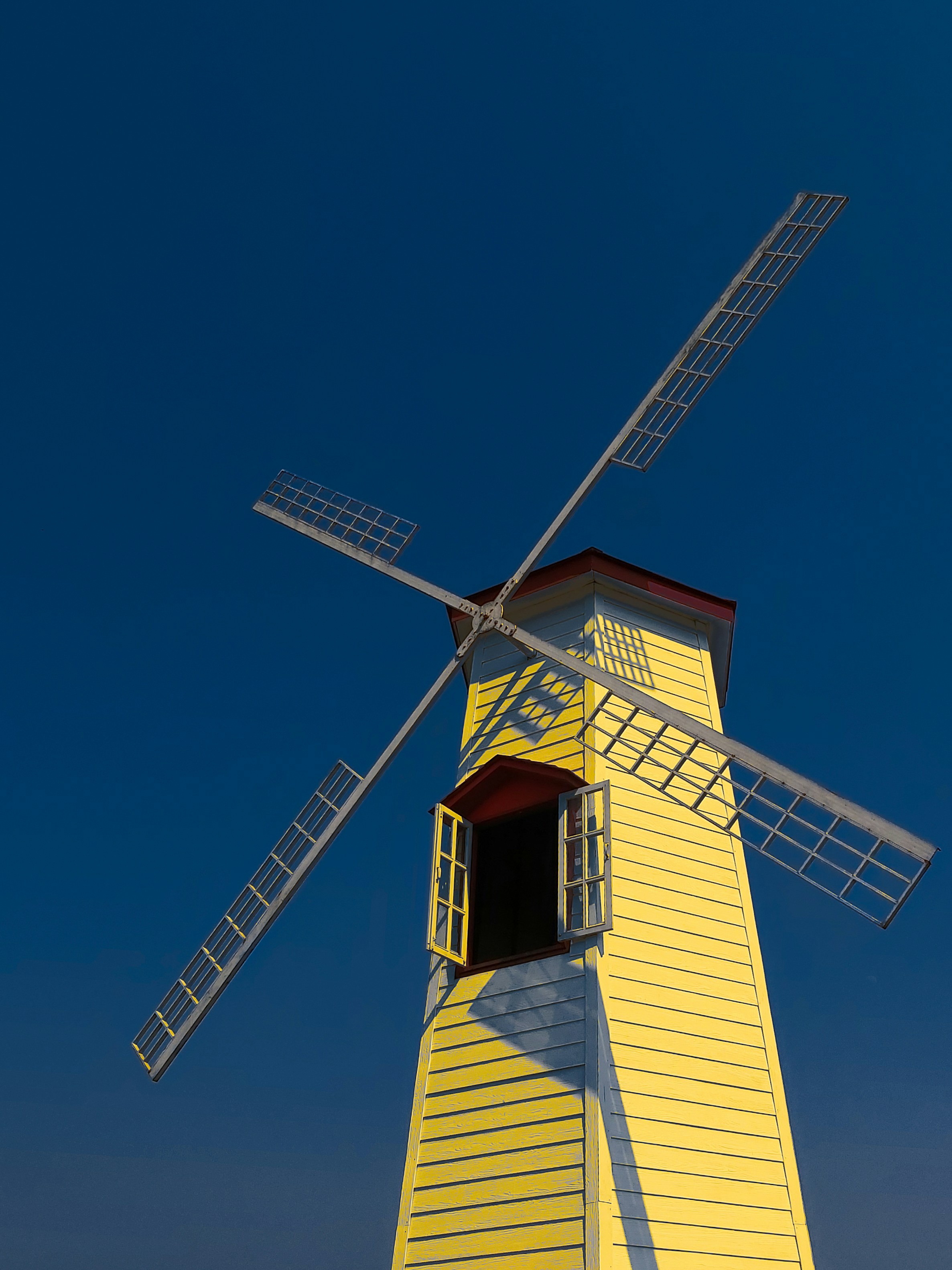A yellow windmill with a red door and window photo – Free Blue abstract ...