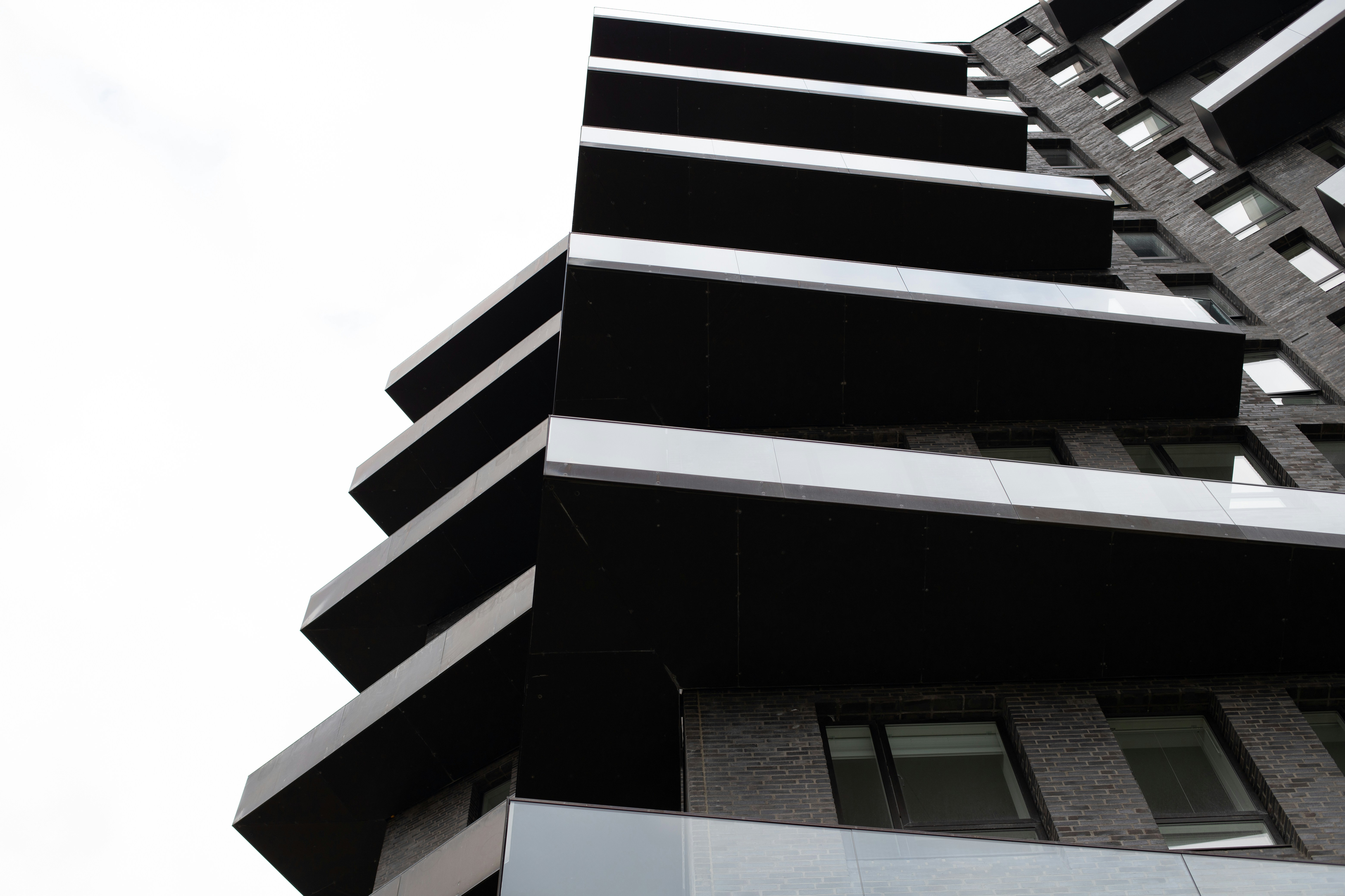 A tall black building with windows and balconies photo – Free ...