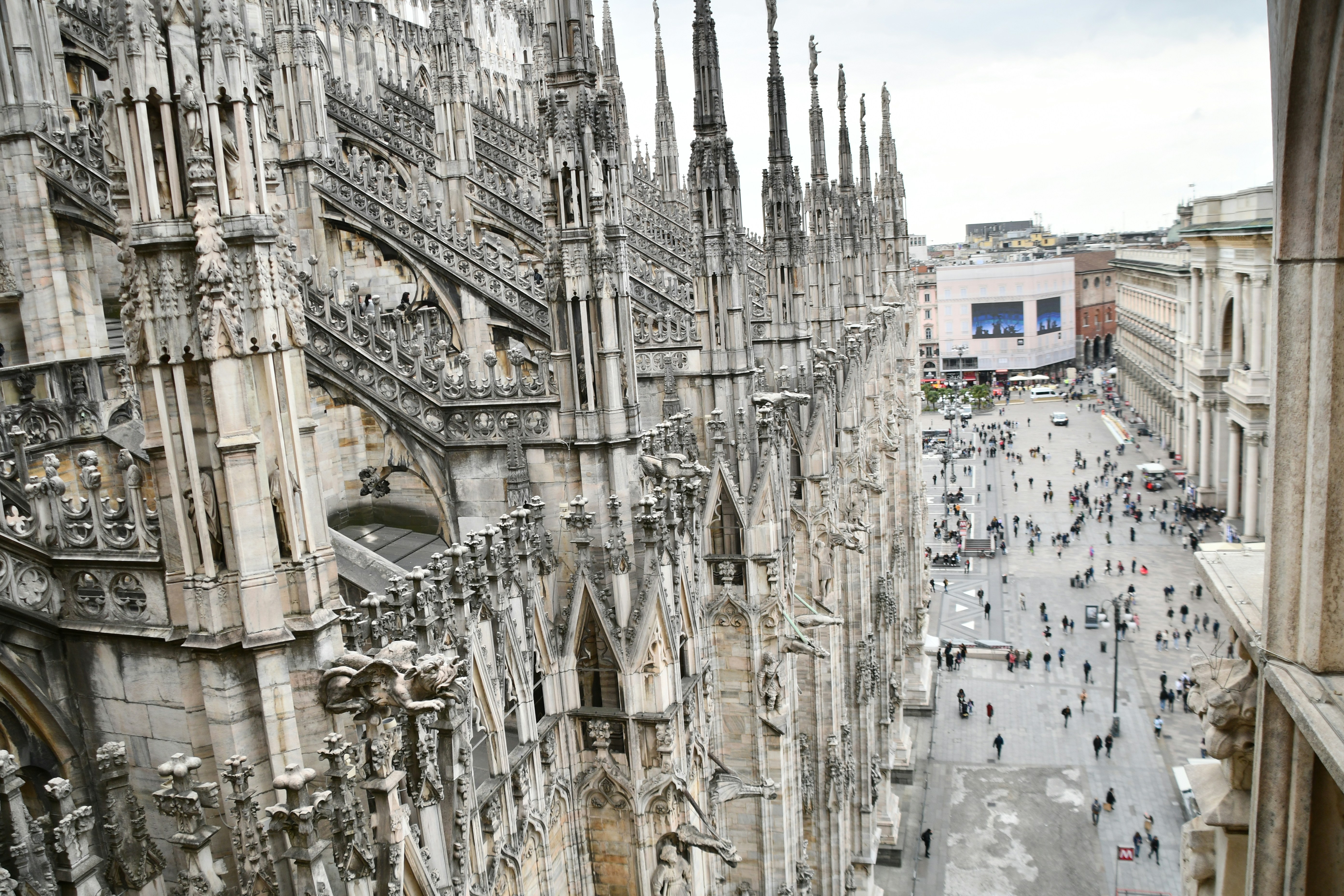 Intricate stone spires of the Duomo di Milano with bustling square below.