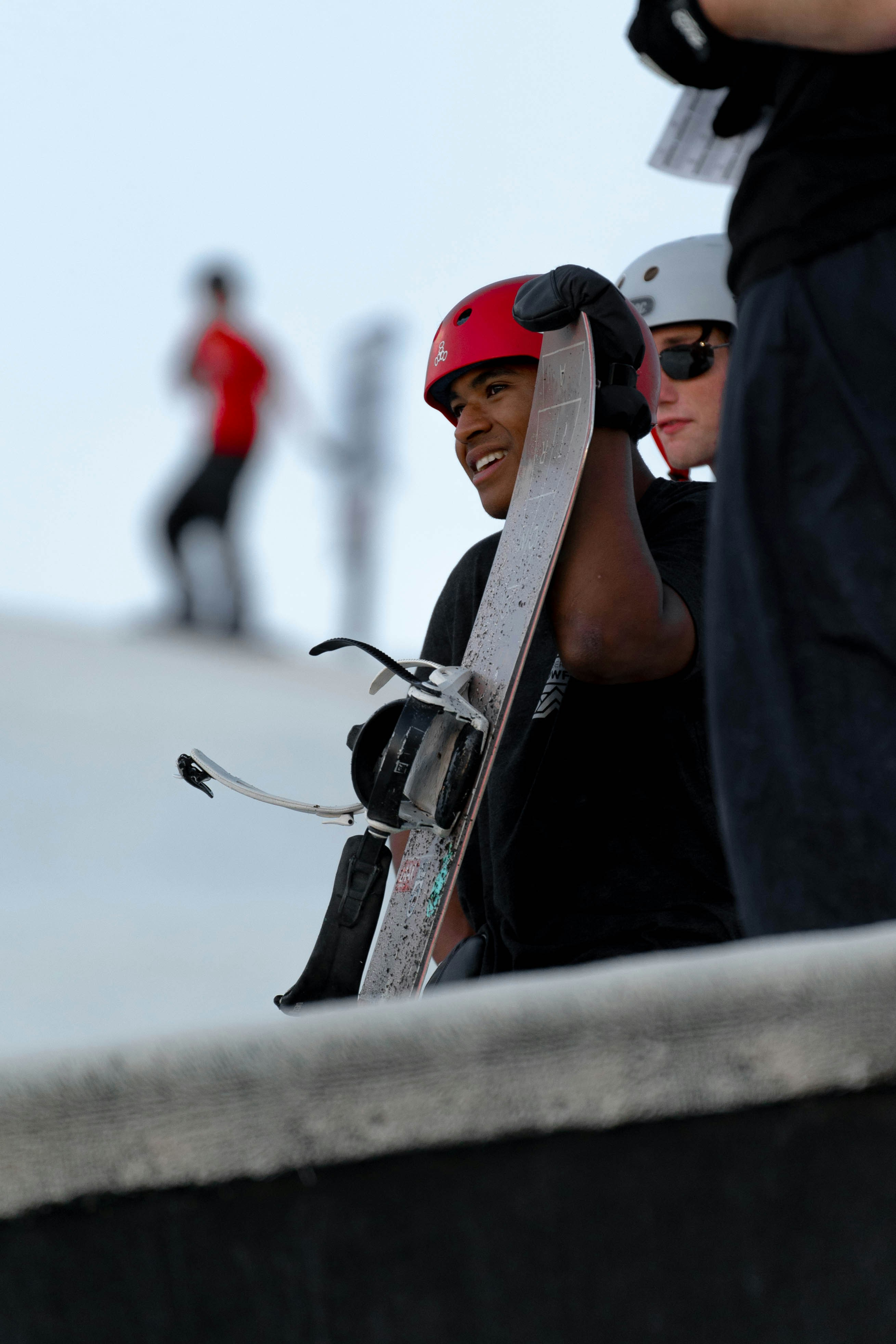 Red-helmeted Skater Holds a Snowboard as the Ramp Scene Comes into Focus
