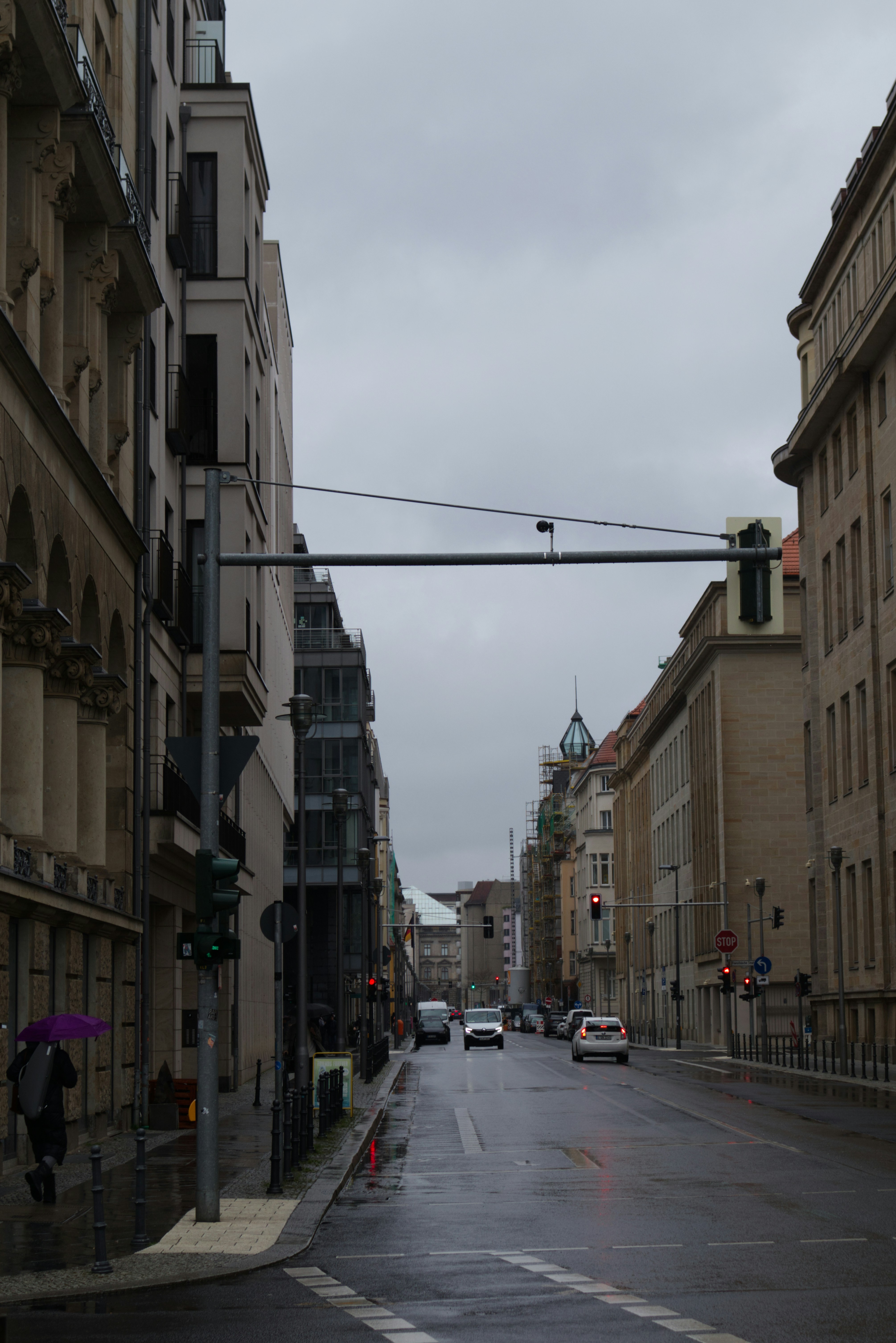 Toward the Distant Light: Rain-Glossed City Street Between Stone Facades