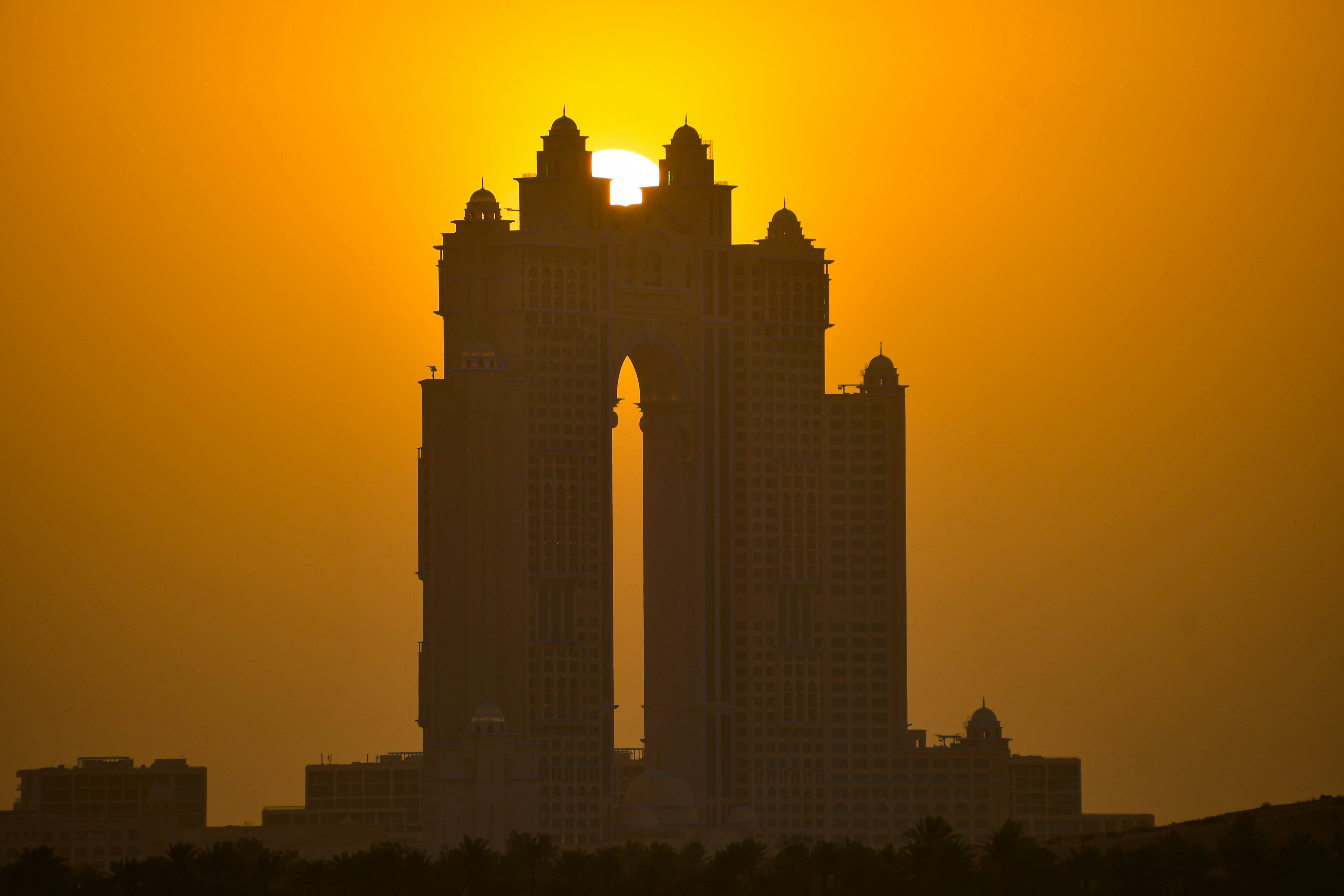 Silhouette of a twin-towered building against a vibrant orange sunset.
