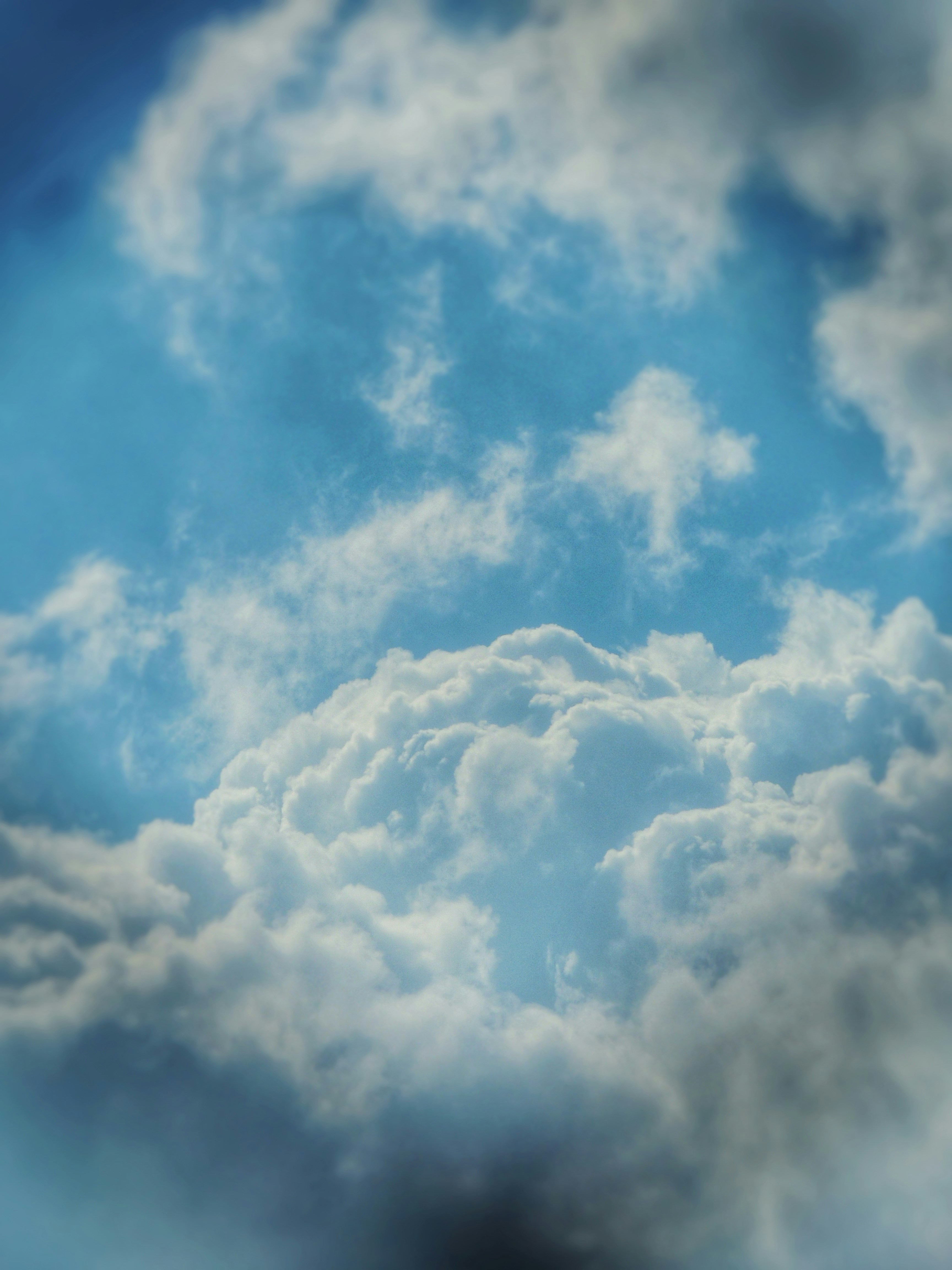 Fluffy clouds intermingling against a bright blue sky, creating a serene atmosphere. The scene evokes a sense of tranquility and wonder.