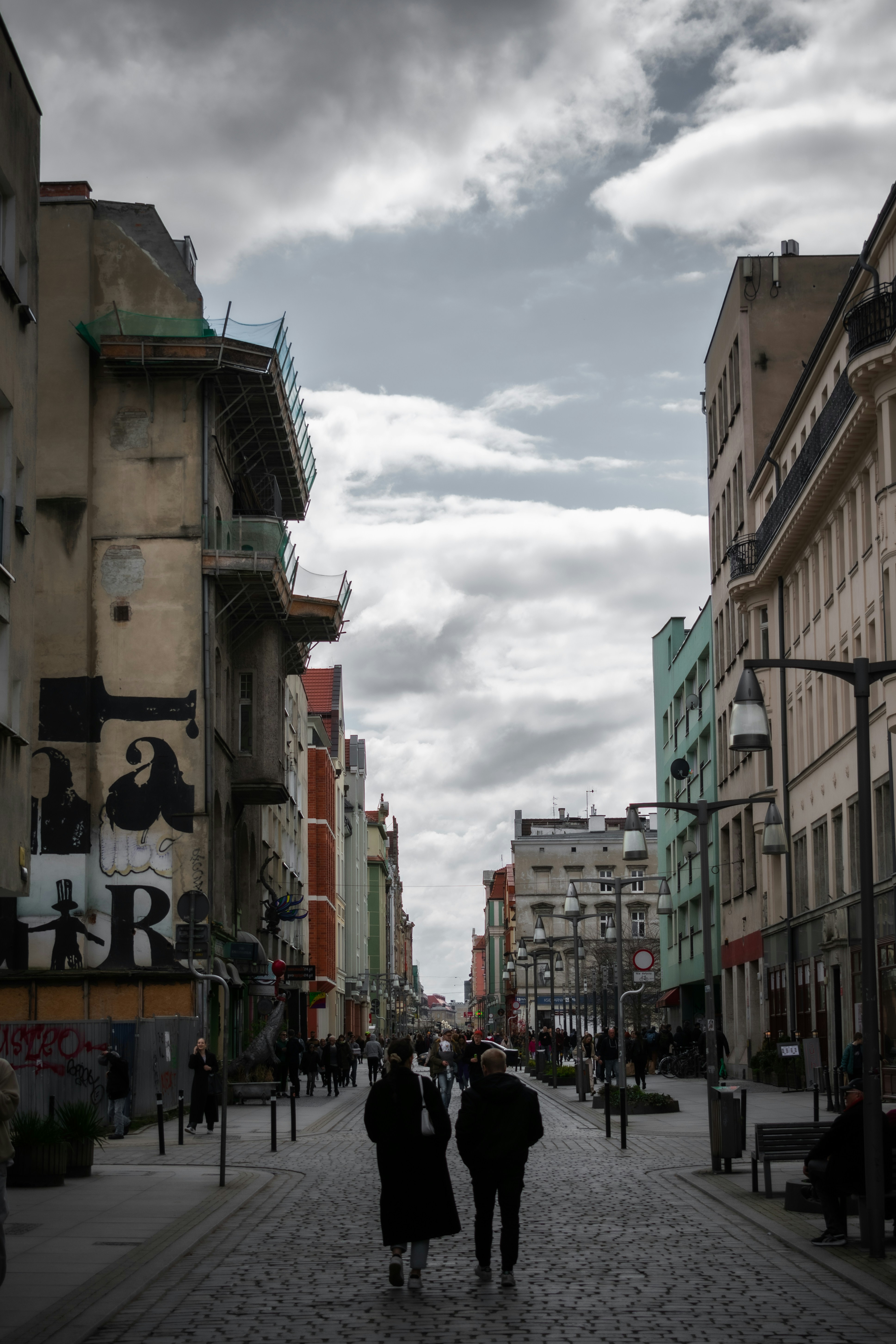 Two Figures, One Path: A Cobblestone Avenue Framed by Colorful Facades