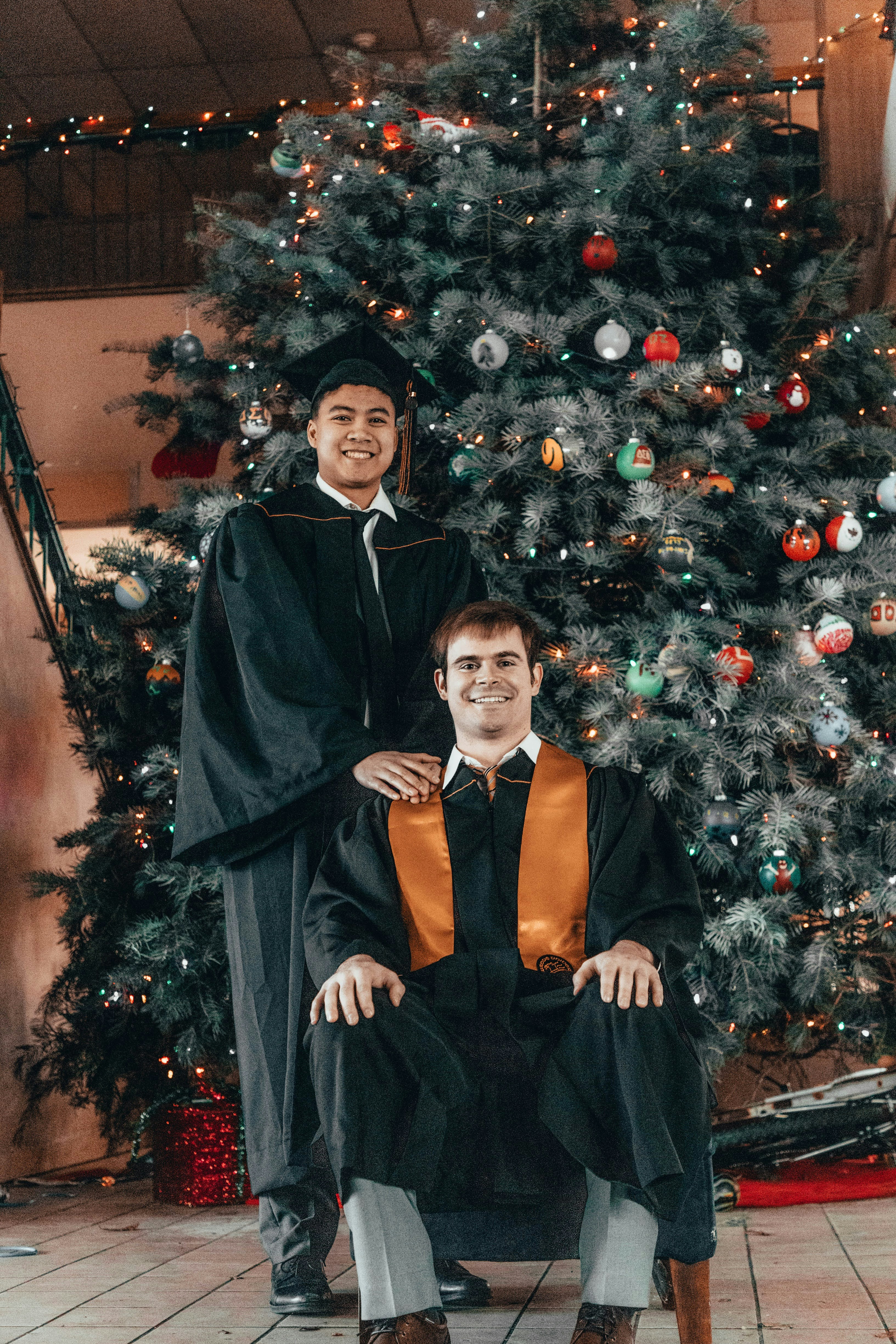 A couple of people that are sitting in front of a christmas tree photo ...