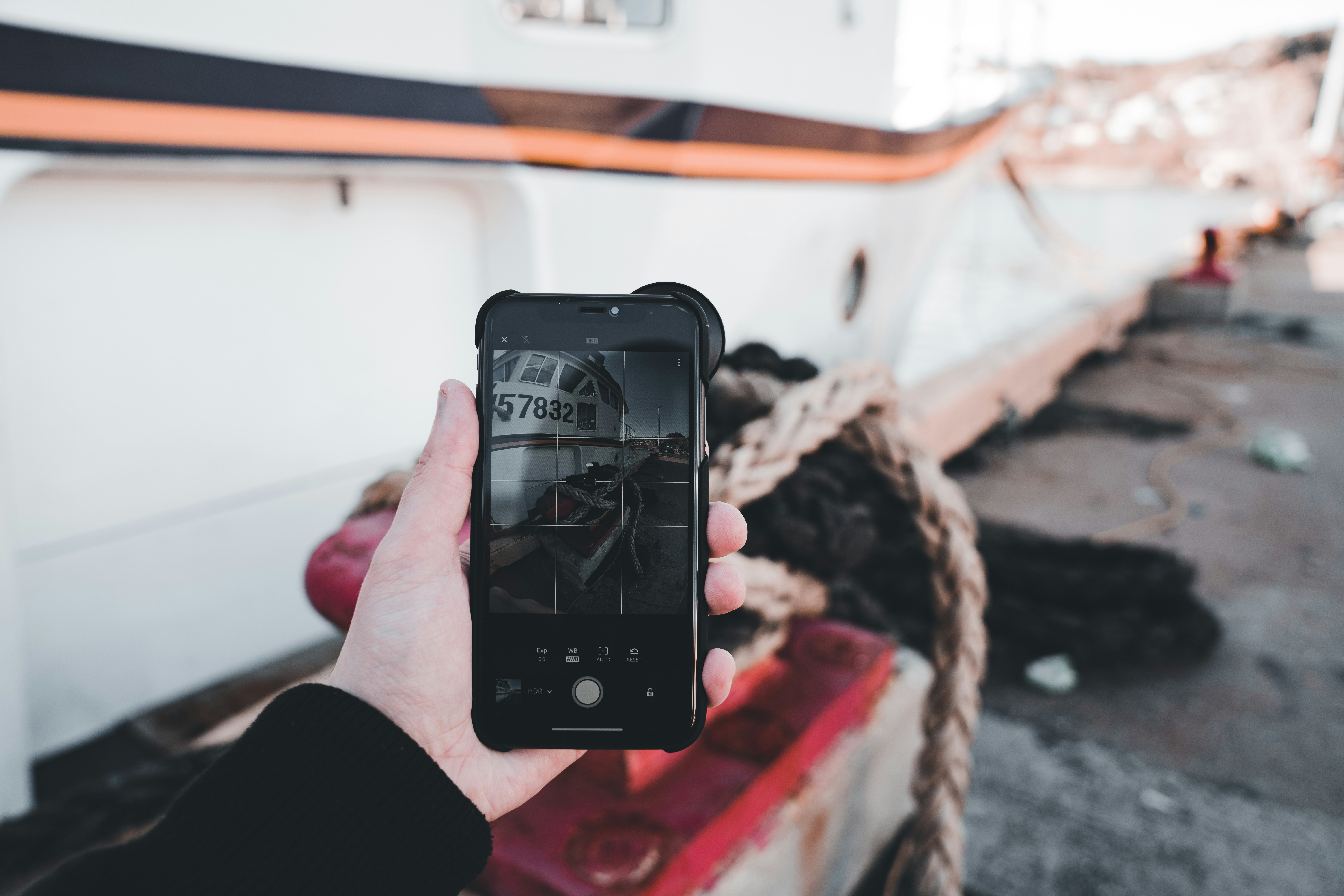 Smartphone Focused on Dockside Bondage: A Handheld Moment by the Ship and Dock
