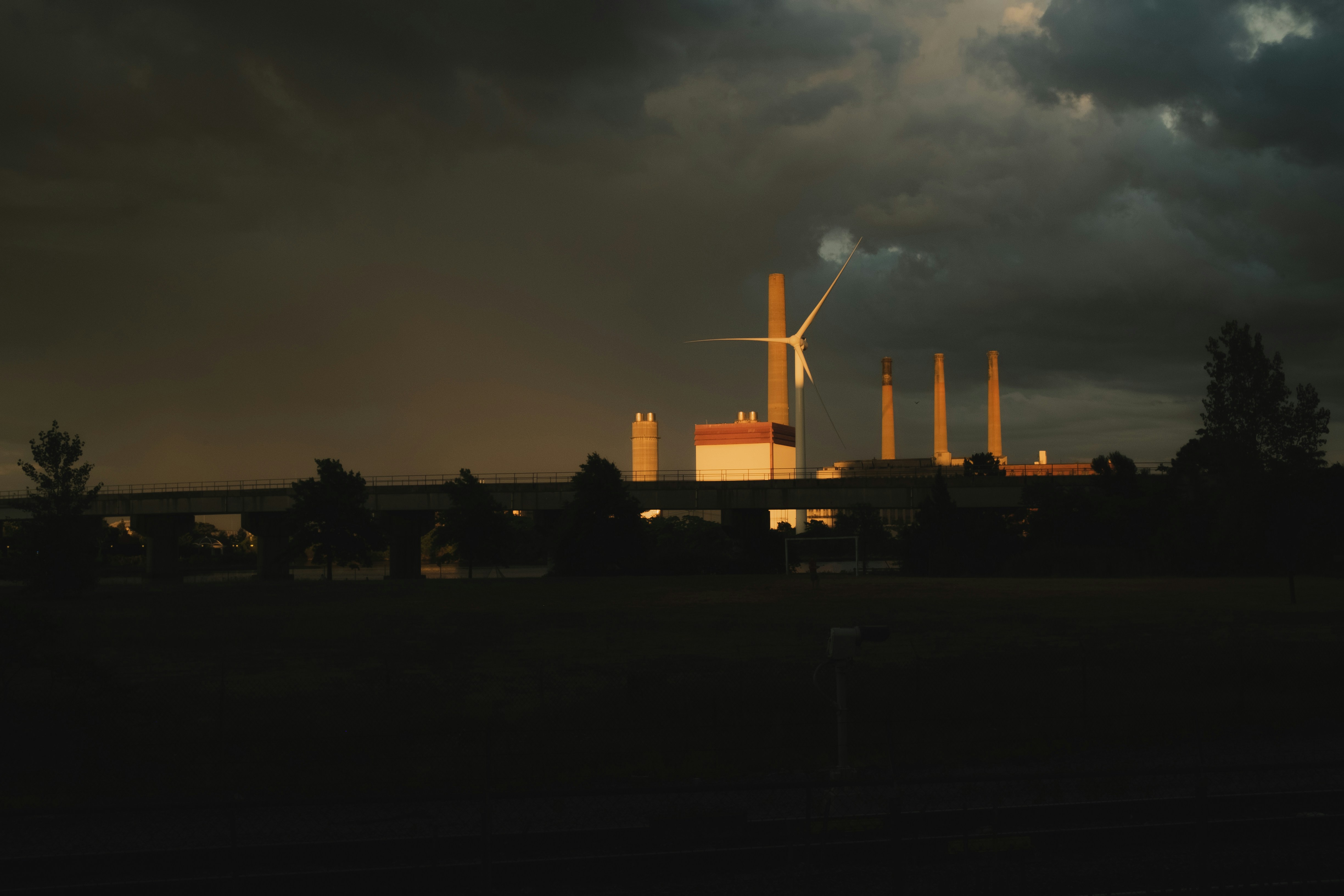Dusk on the Ridge: Sunlit Turbine Above a Quiet Industrial Horizon
