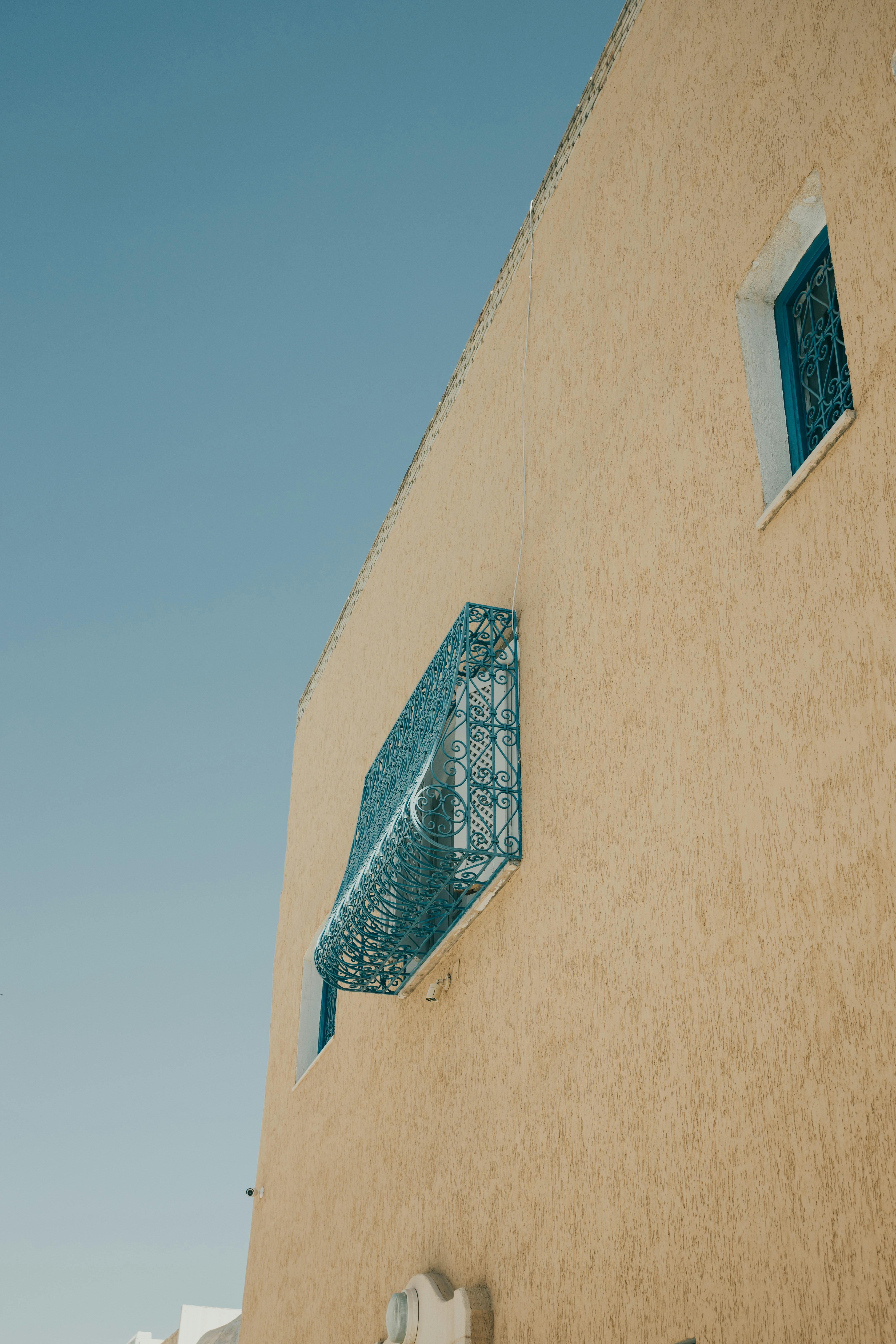 A tan building with a blue window and a blue awning photo – Free Wall ...