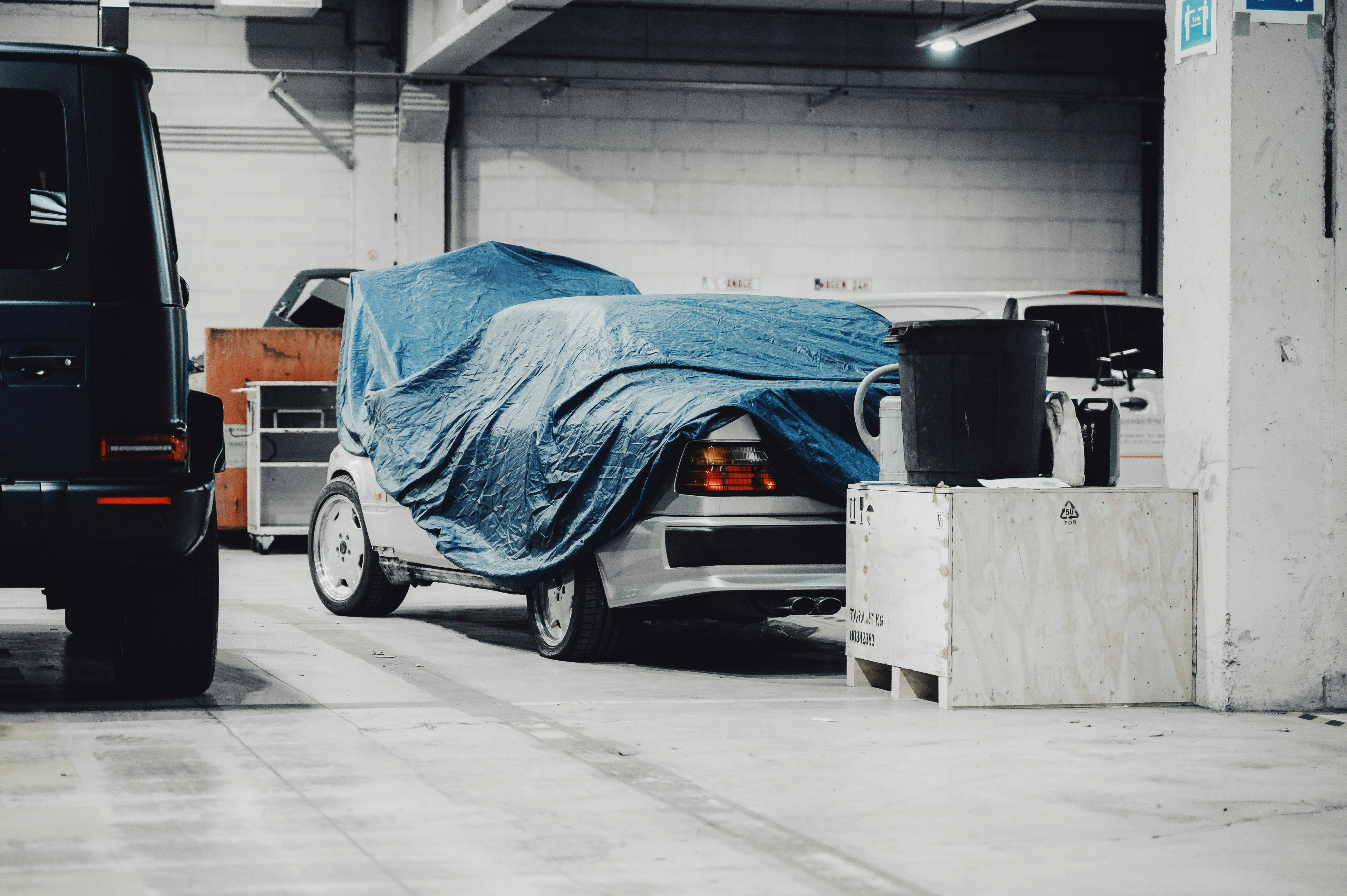 A car covered in a blue tarp in a garage photo – Free Car Image on Unsplash