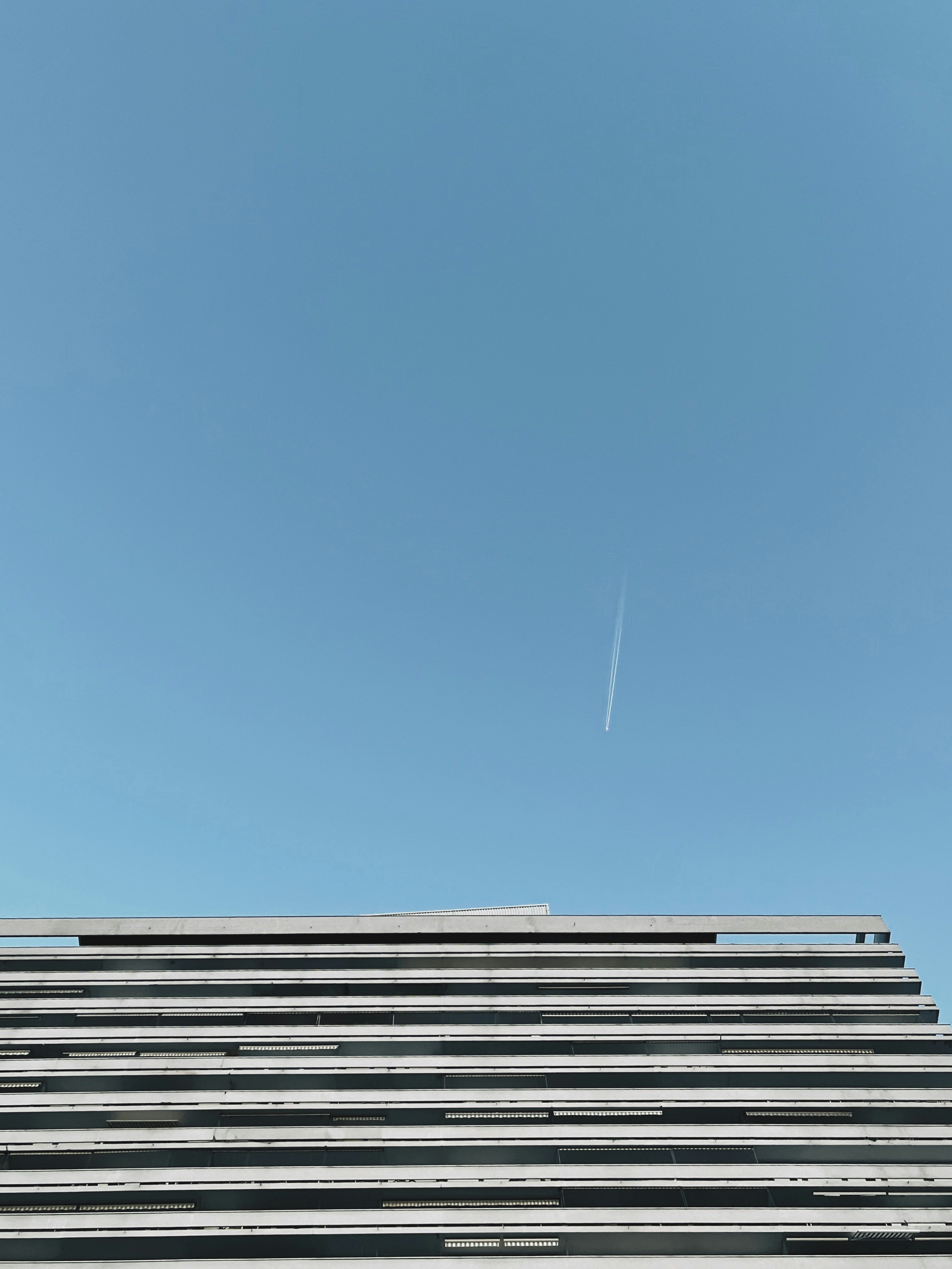 A tall building with a plane flying in the sky photo – Free Image on ...