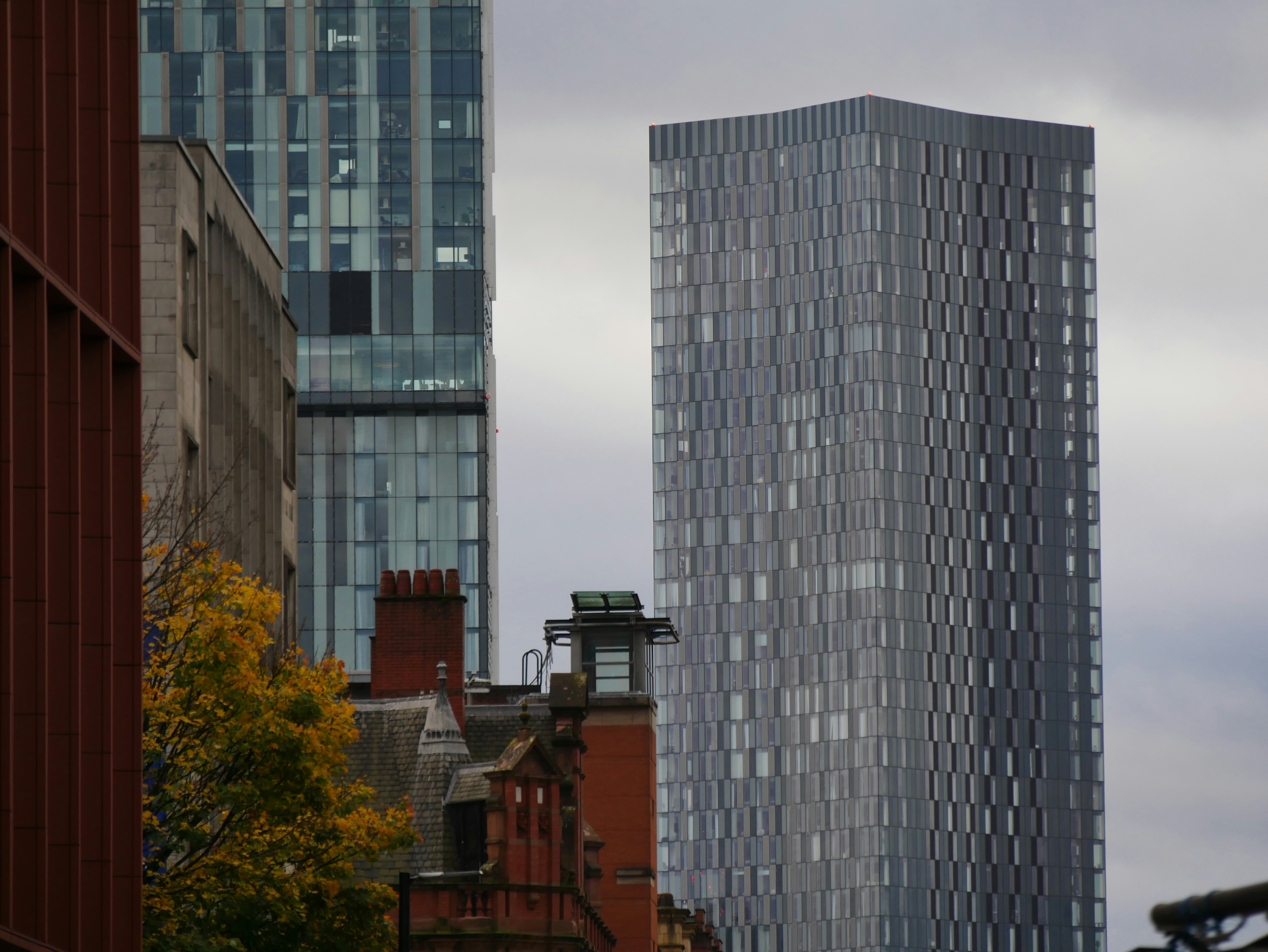 A view towards Deansgate Square's West Tower from Deansgate, framed by the Beetham Tower. | a very tall building next to a very tall building