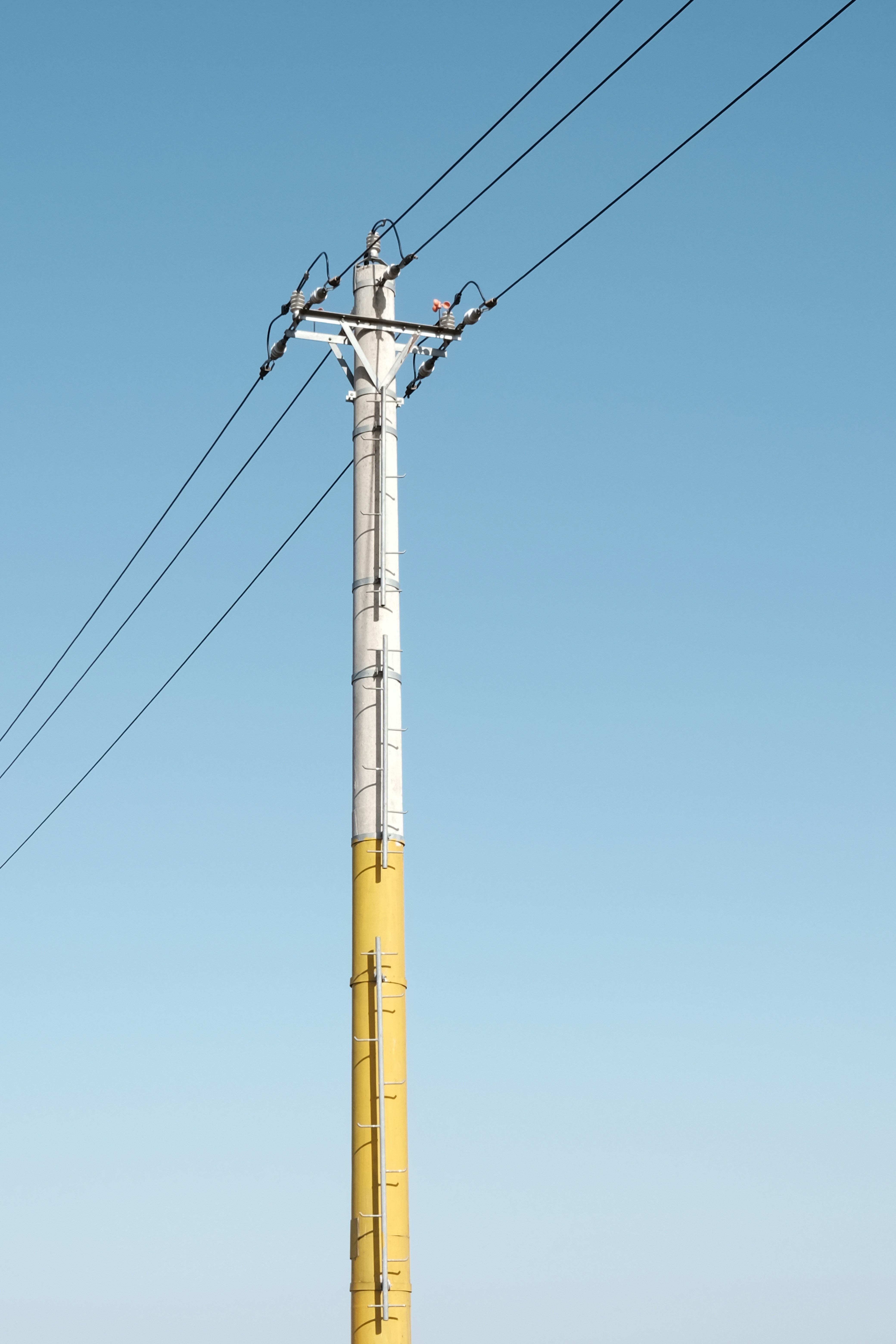 A yellow and white pole with power lines above it photo – Free Yellow ...