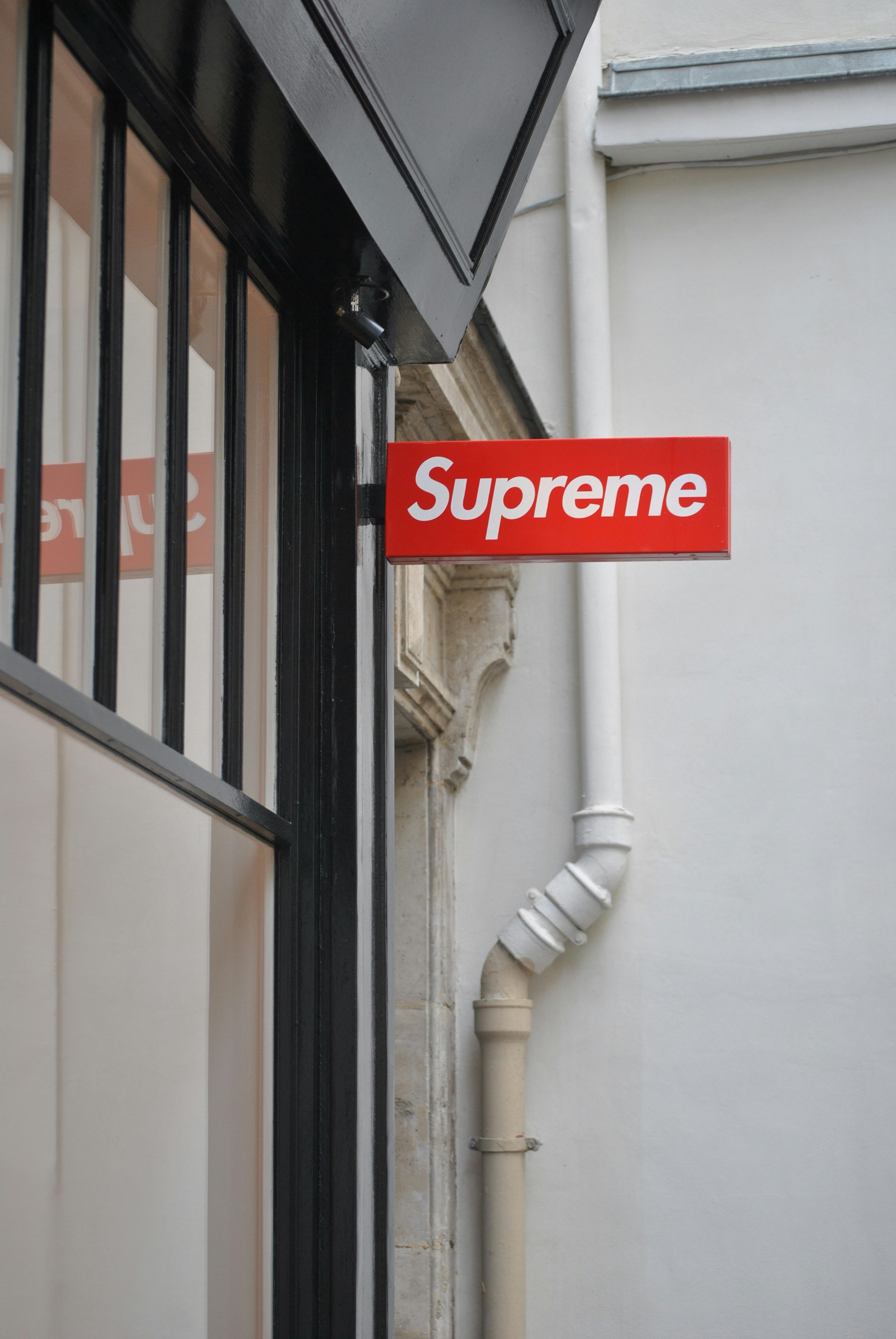 A red supreme sign hanging from the side of a building photo – Free ...
