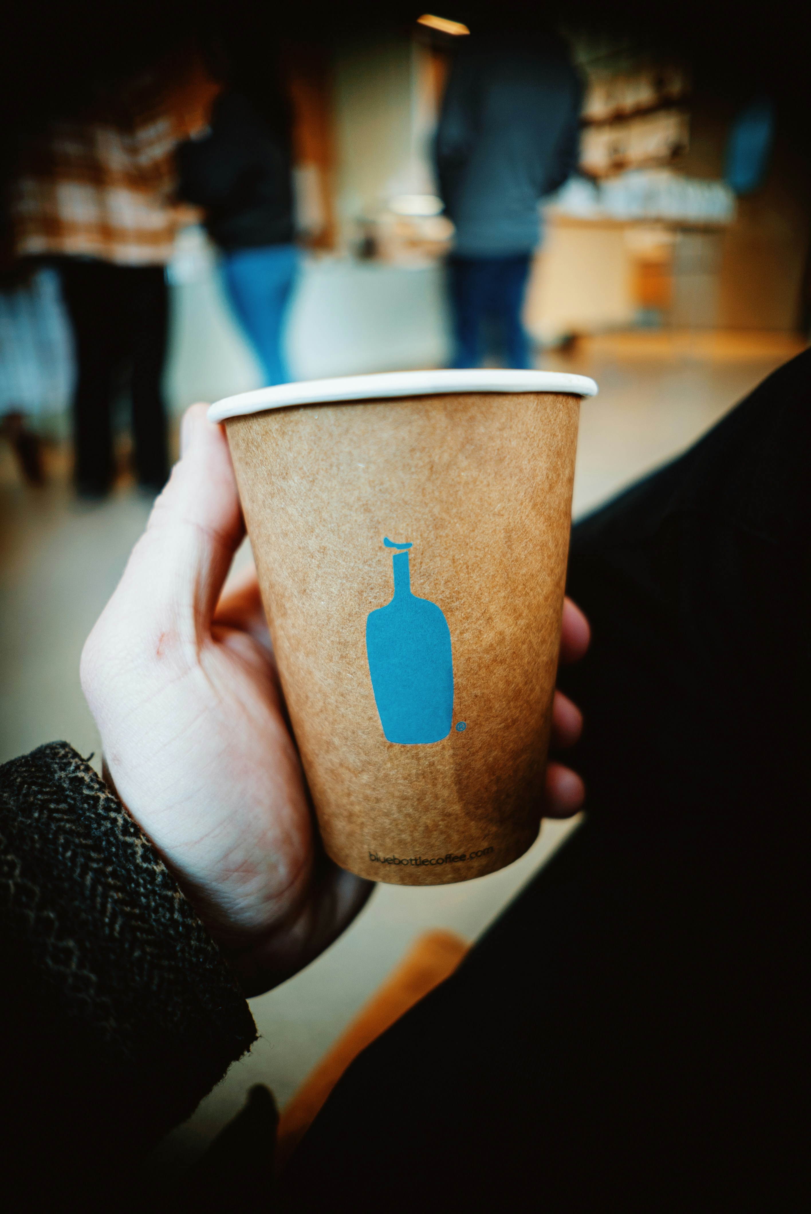 a person holding a cup with a blue bottle on it