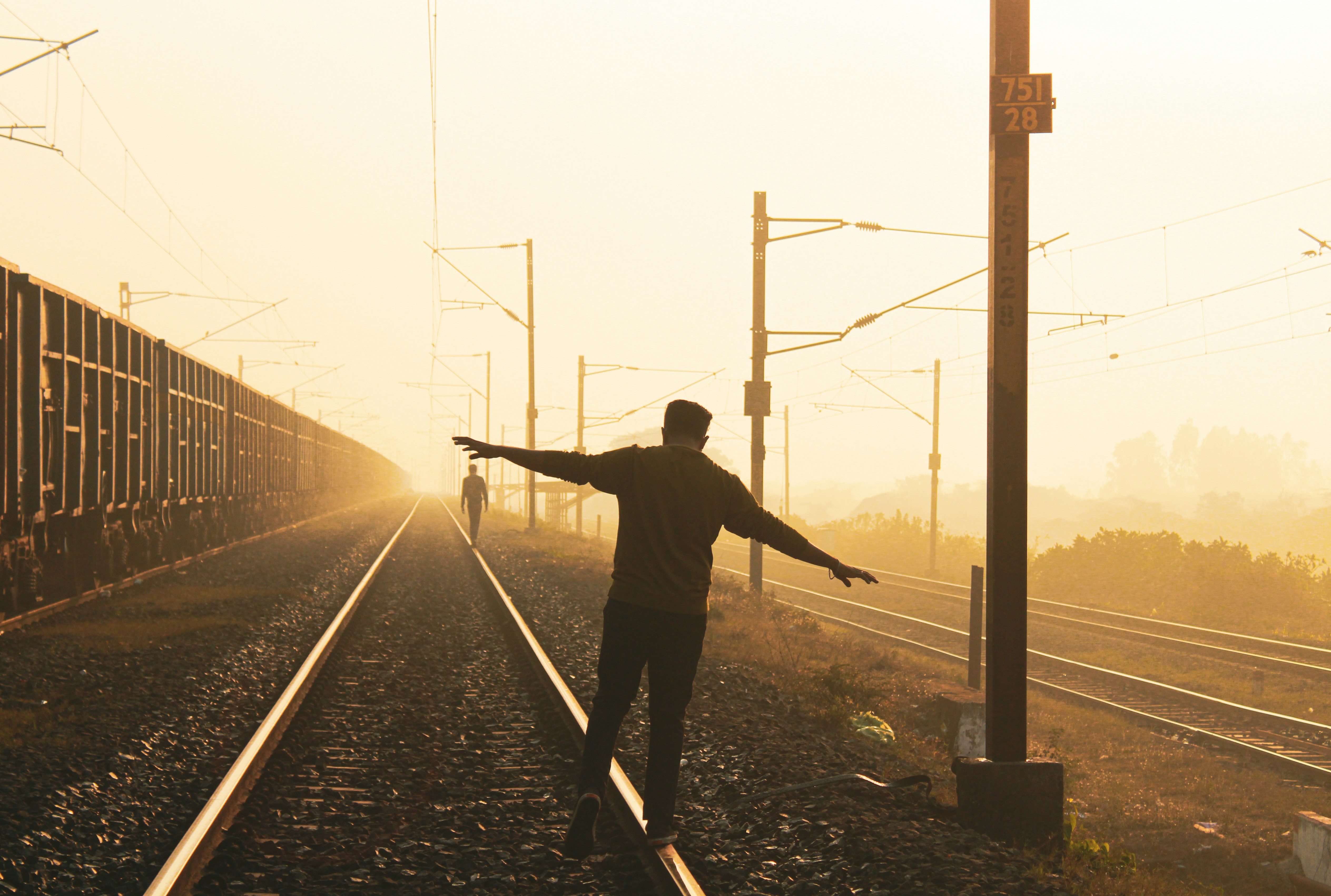 A man standing on a train track pointing to the sky photo – Free ...