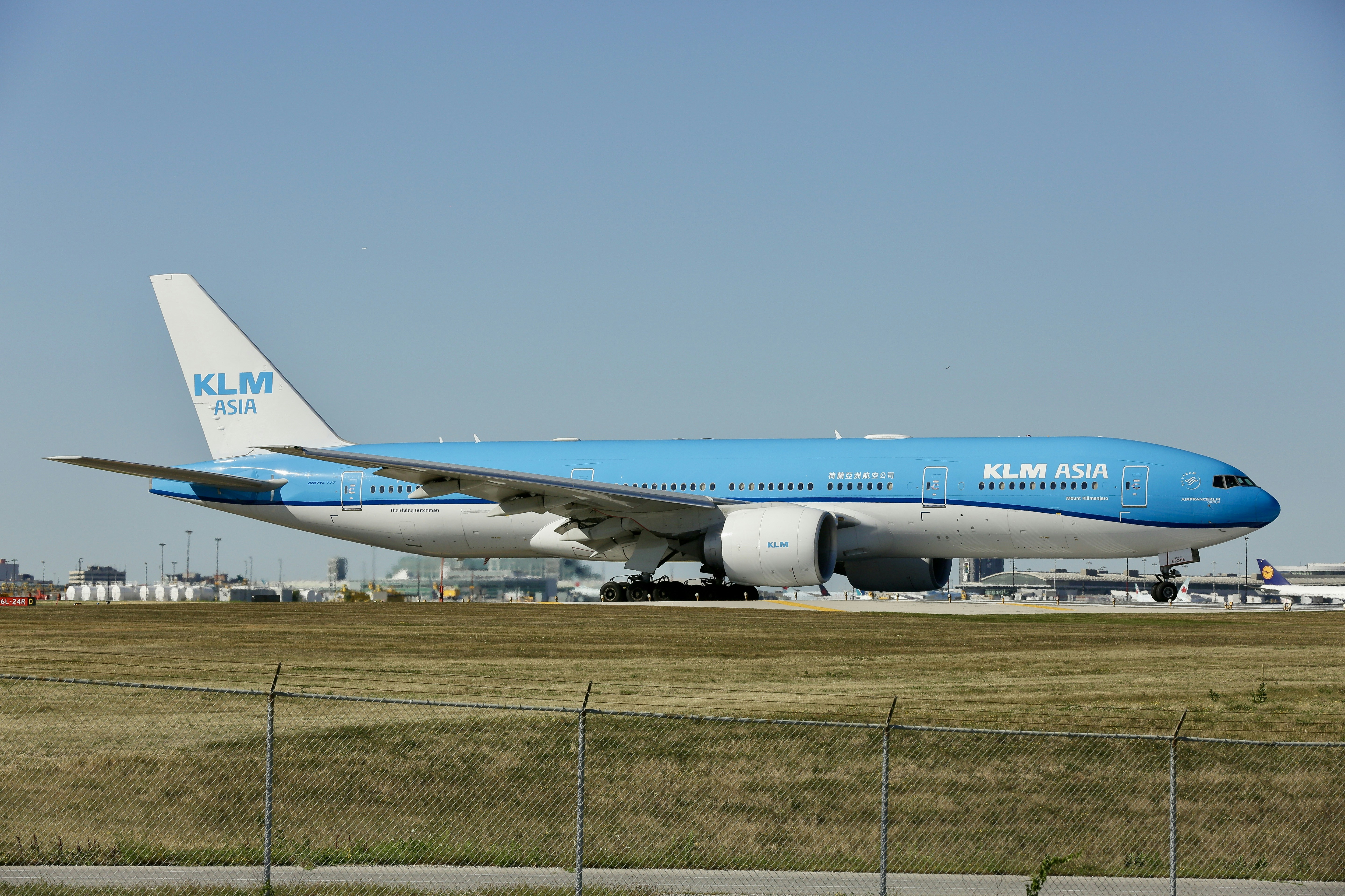 A large blue and white jetliner sitting on top of an airport runway ...