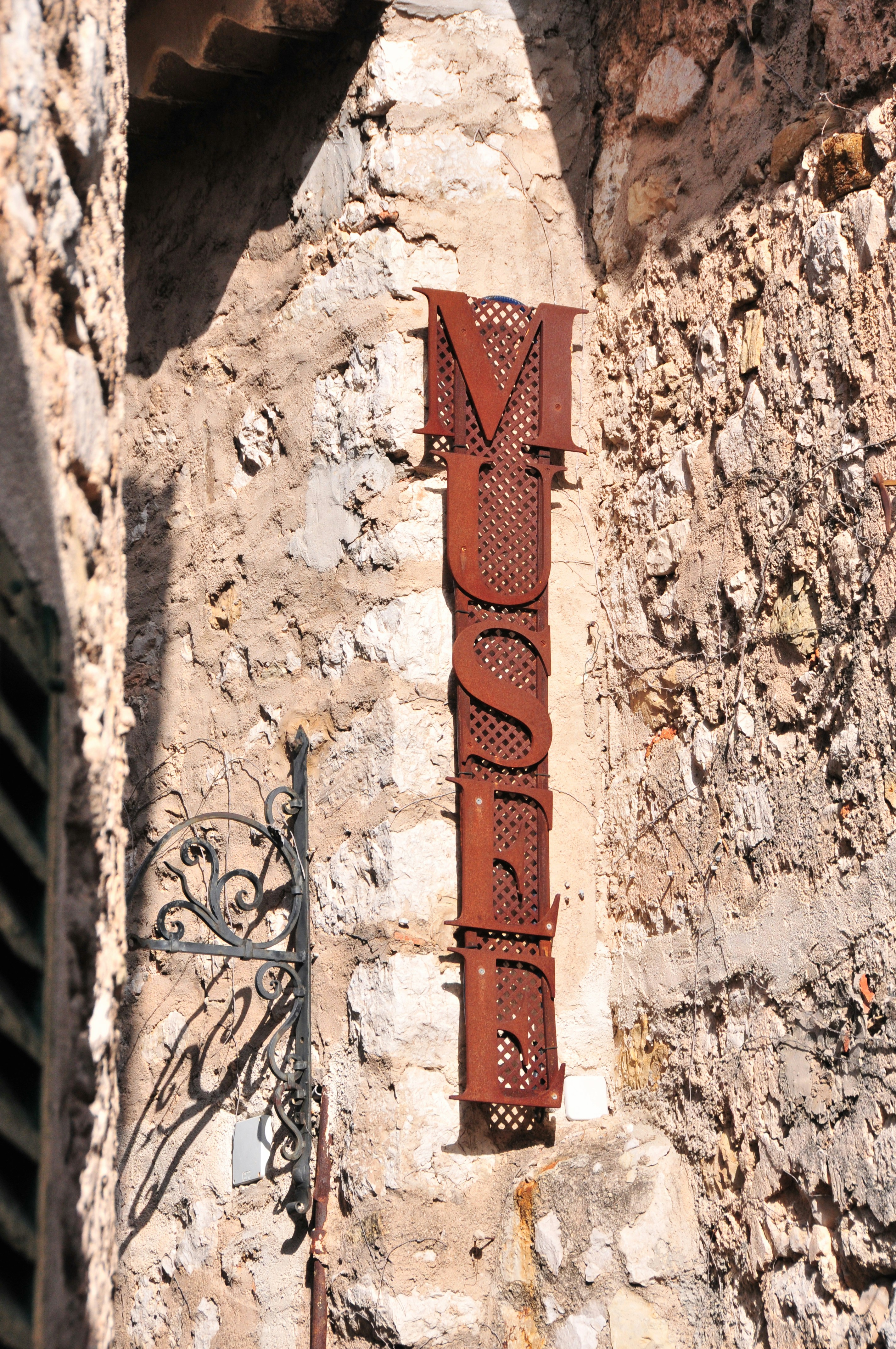 MUSEO in Rust: A Vertical Sign Anchored to Sunlit Stone