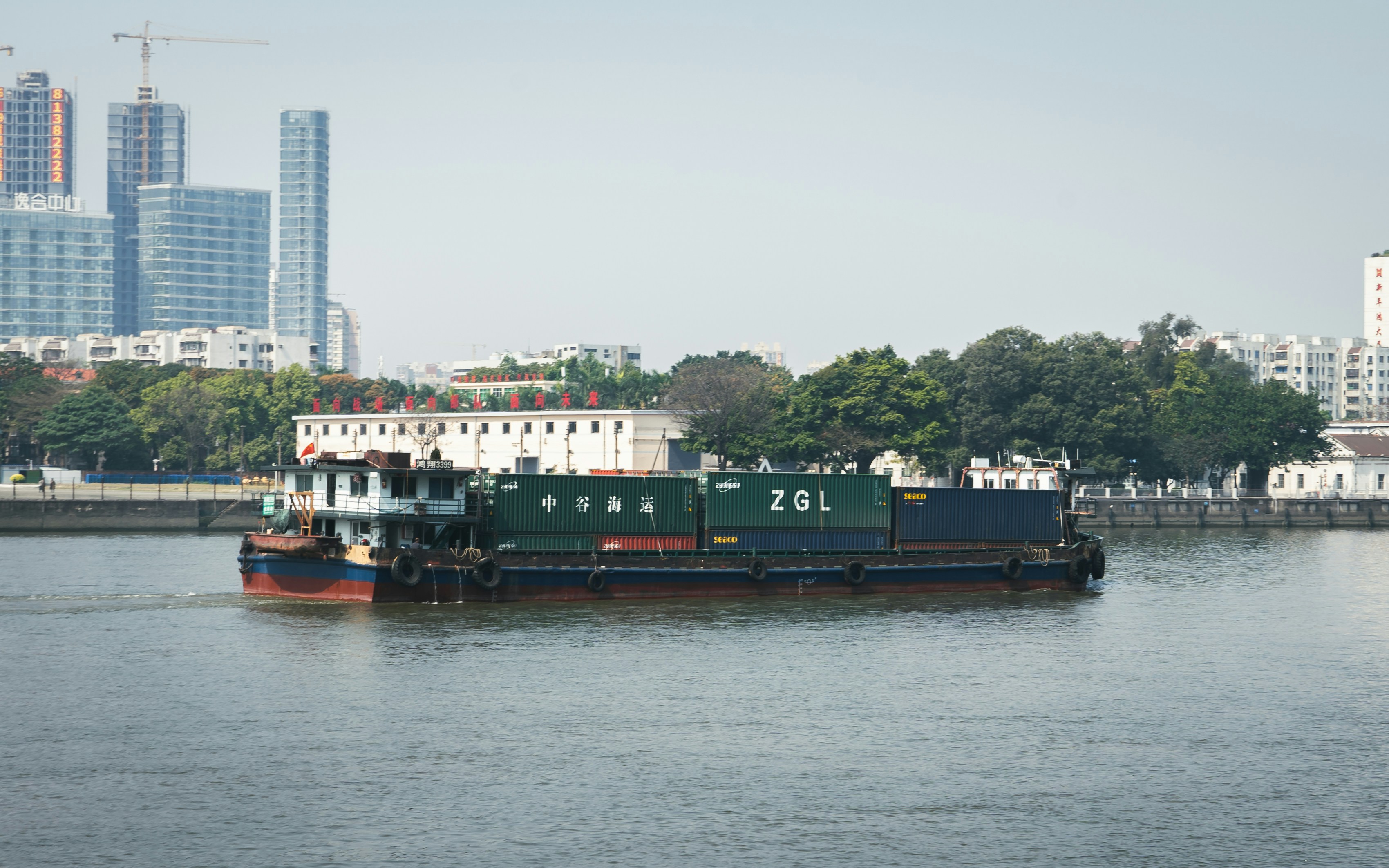 ZGL Container Barge Over a Quiet River, Framed by a Modern City Skyline