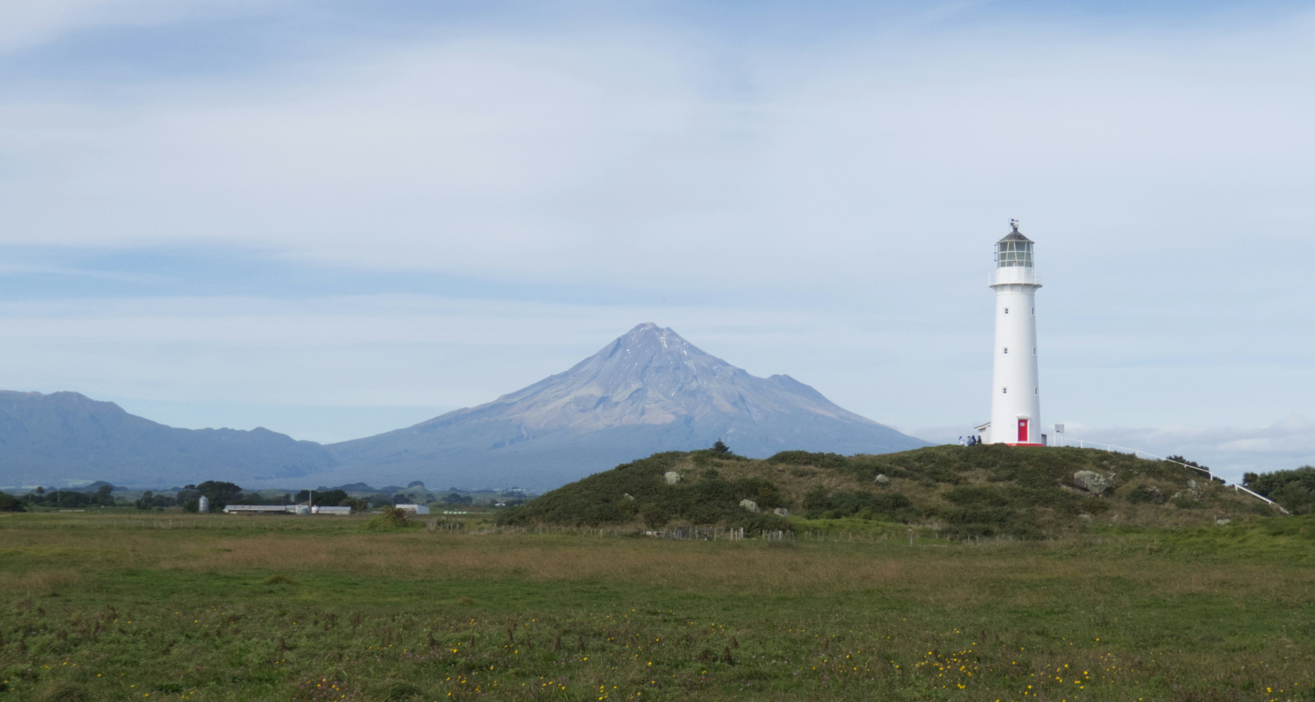 Beacon on the Moor: Lighthouse Framing a Distant Conical Peak