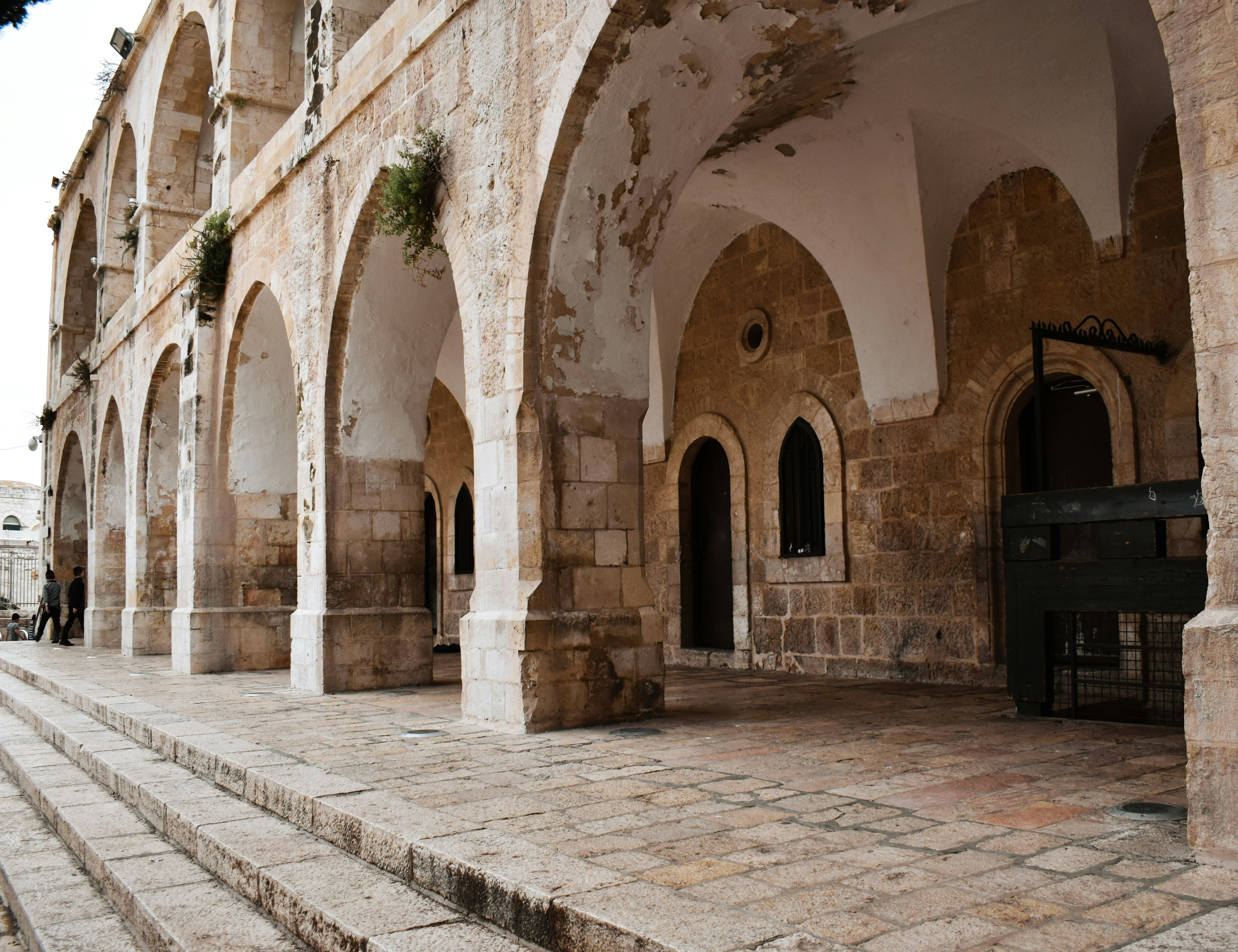 Ancient stone arches line a weathered building facade in Jerusalem's Old City.