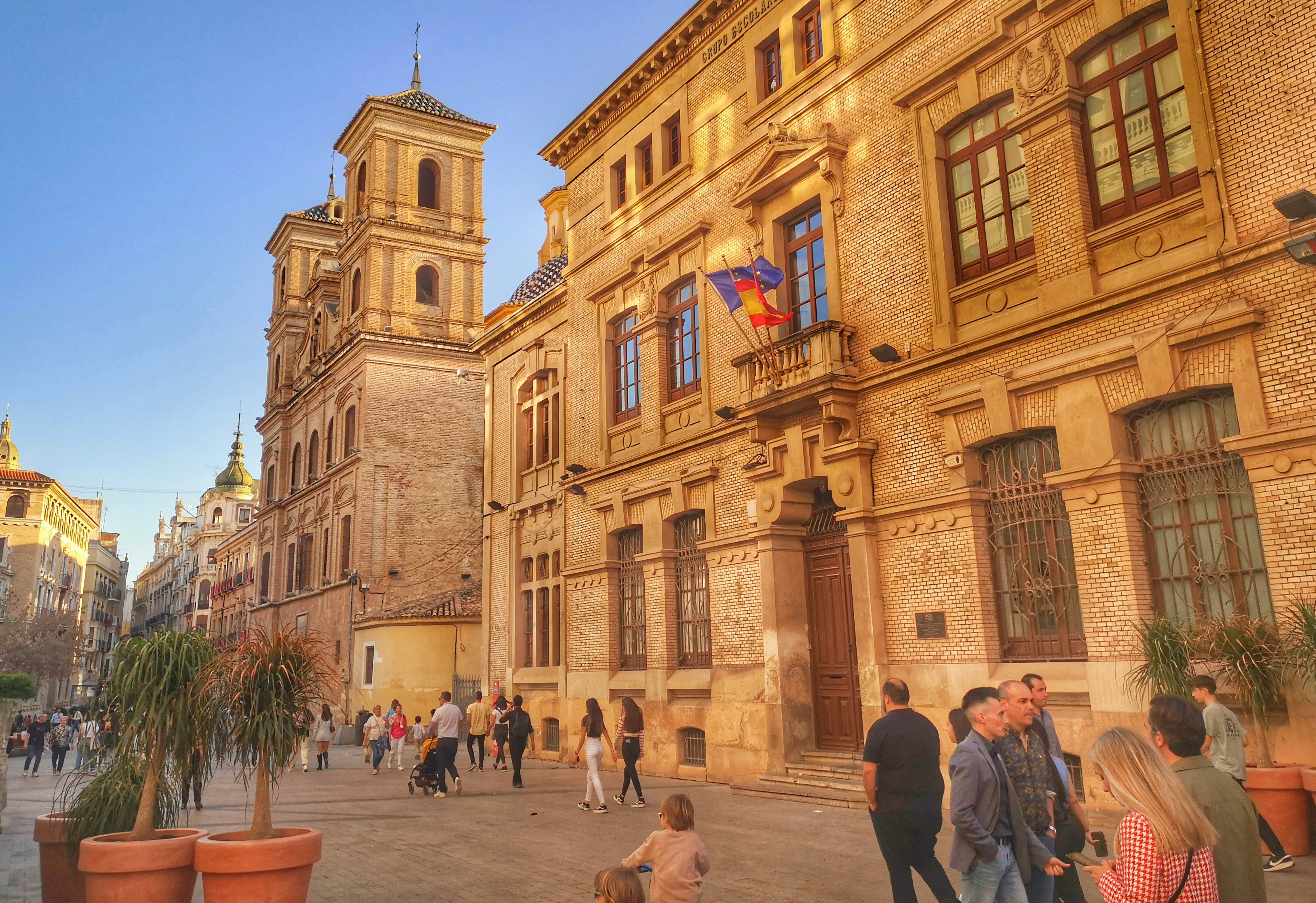 a group of people walking down a street next to tall buildings