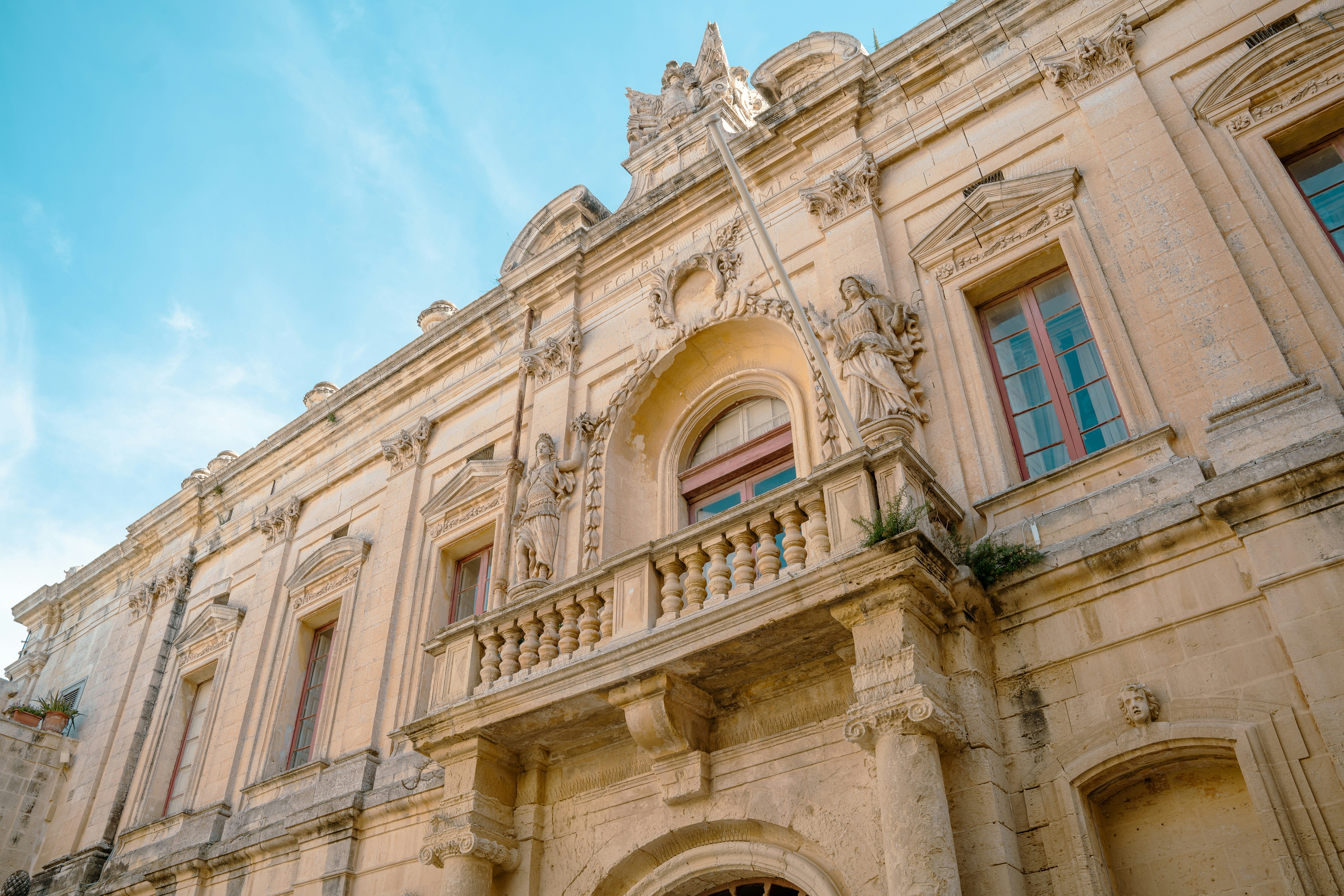 Renaissance architecture building captured from a low angle with intricate stonework against a bright blue sky.