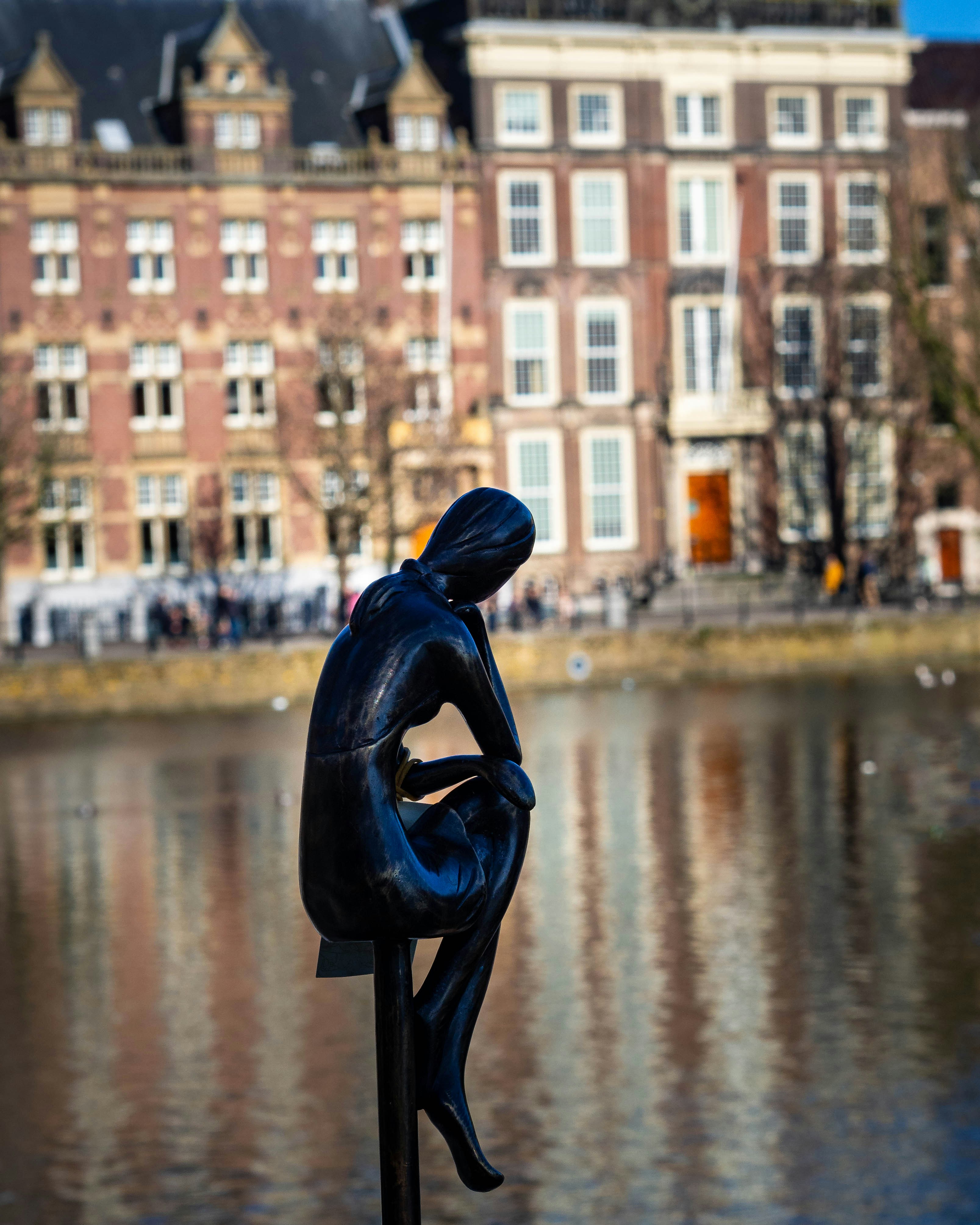 A statue of a person sitting in front of a body of water photo – Free ...
