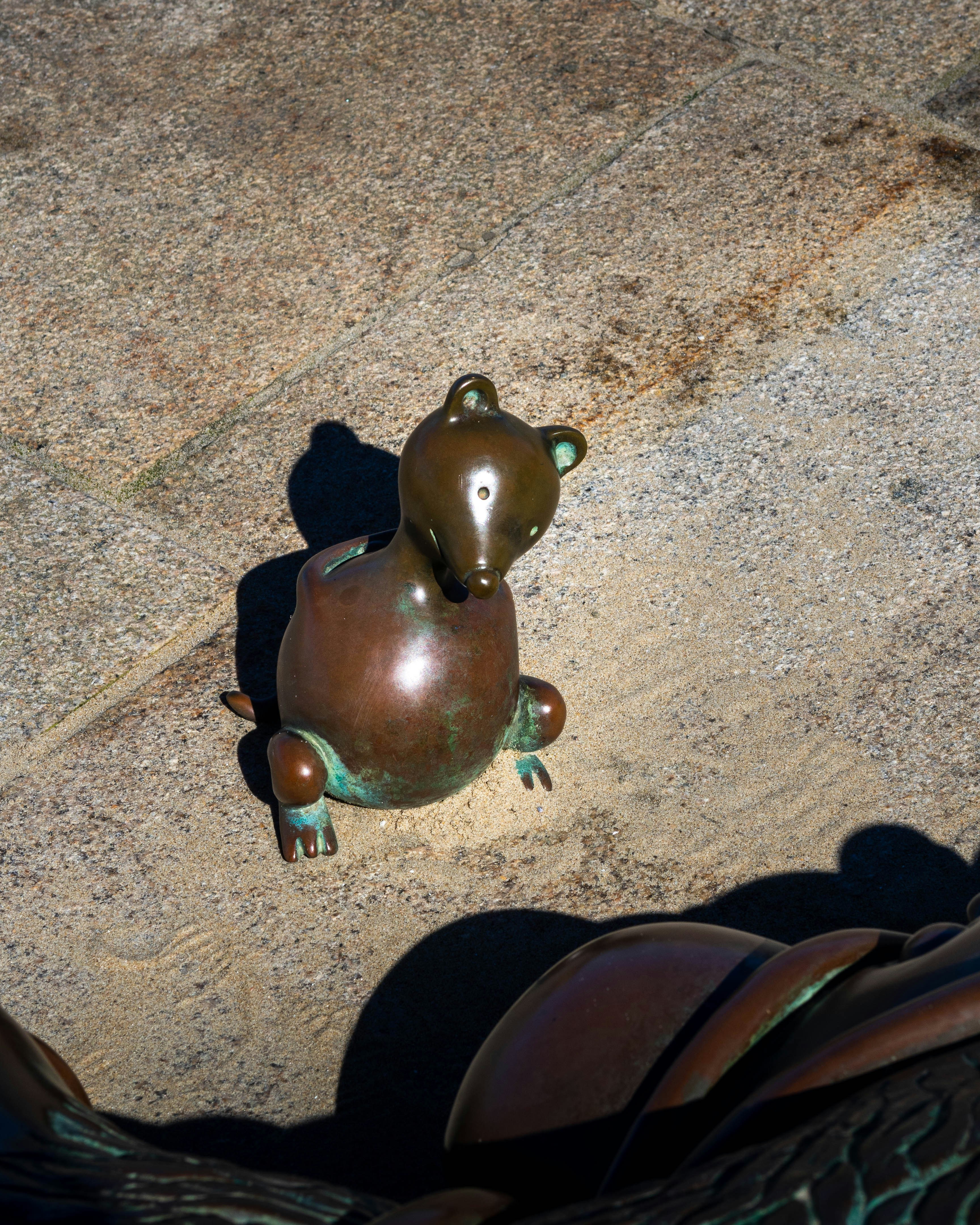 Bronze Bear on Sunlit Paving: A Tiny Urban Sentinel