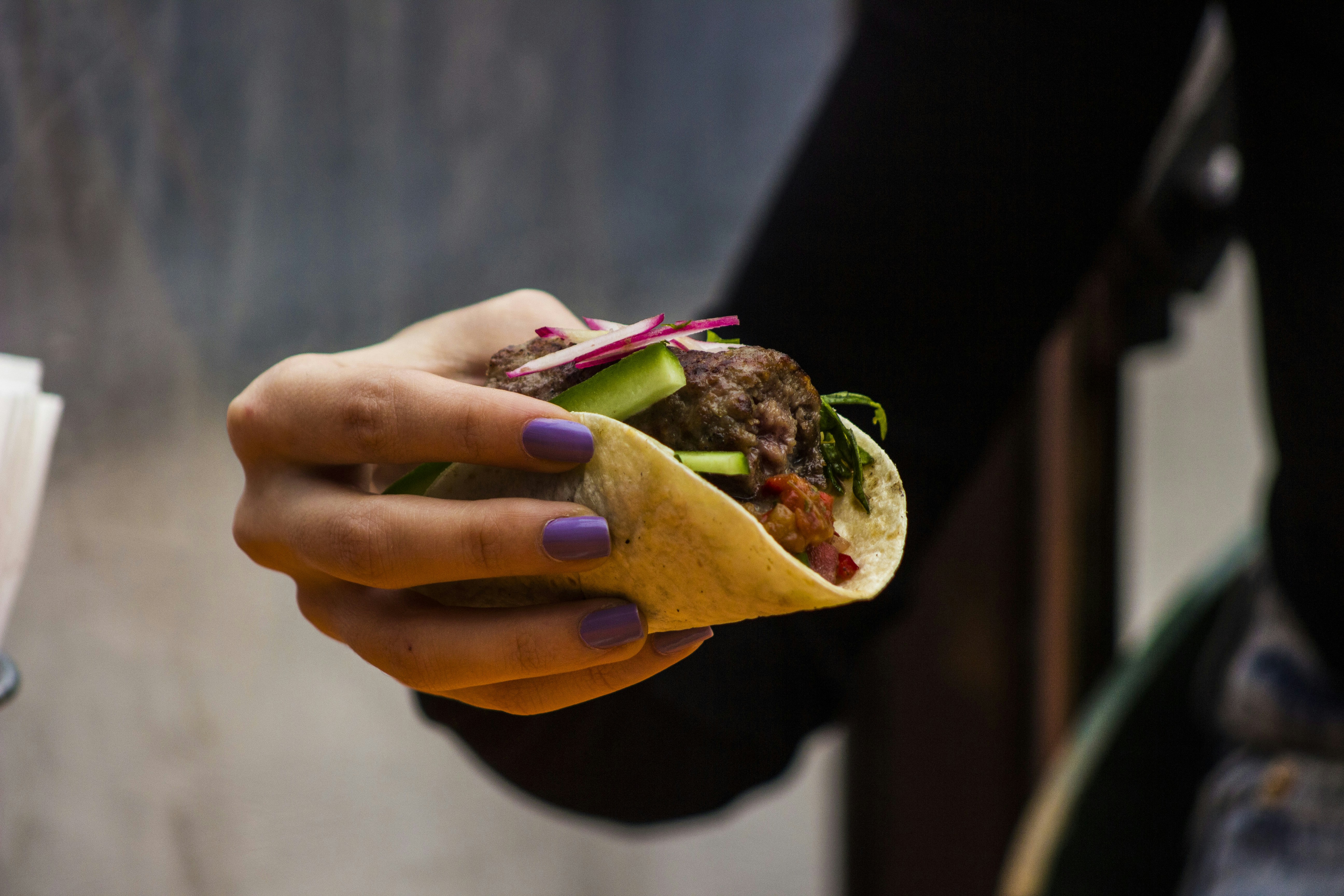 Crave-Worthy Handful: A Taco in Focus with Violet Nails