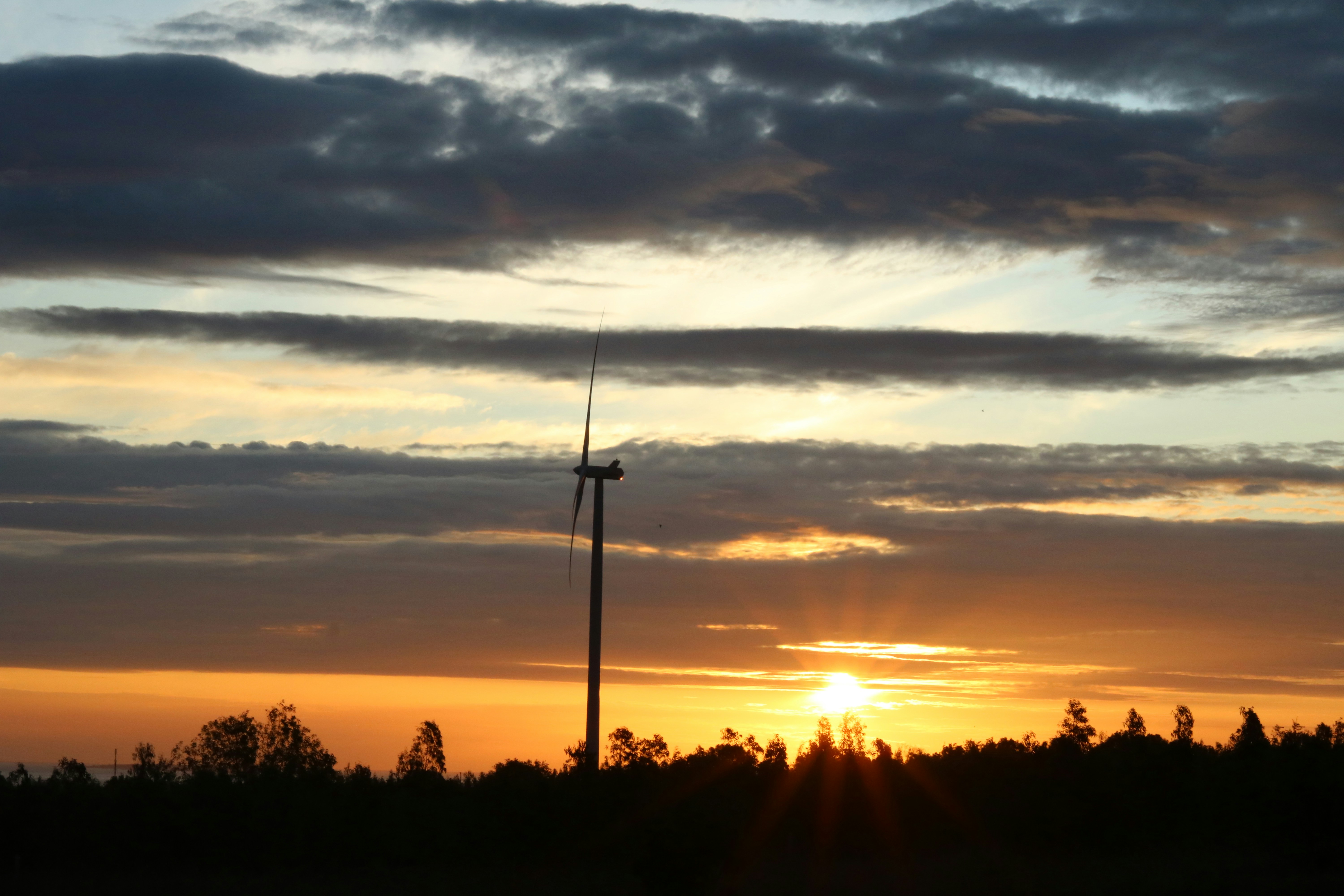 Sunlit Mast at Dusk: Wind Turbine Silhouette Against a Golden Horizon