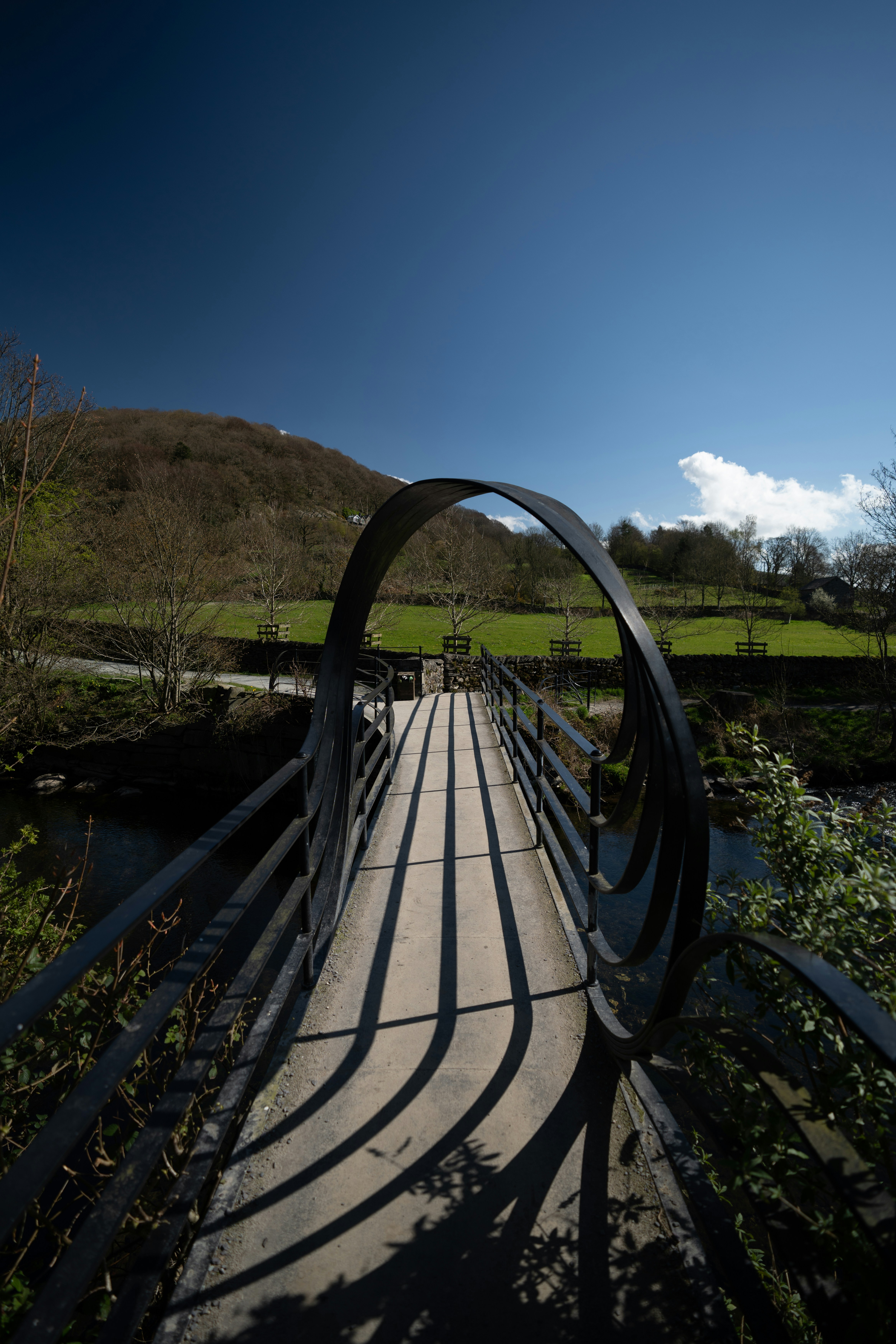 Arching Steel Path: A Quiet Bridge Looping Over a Reflective River